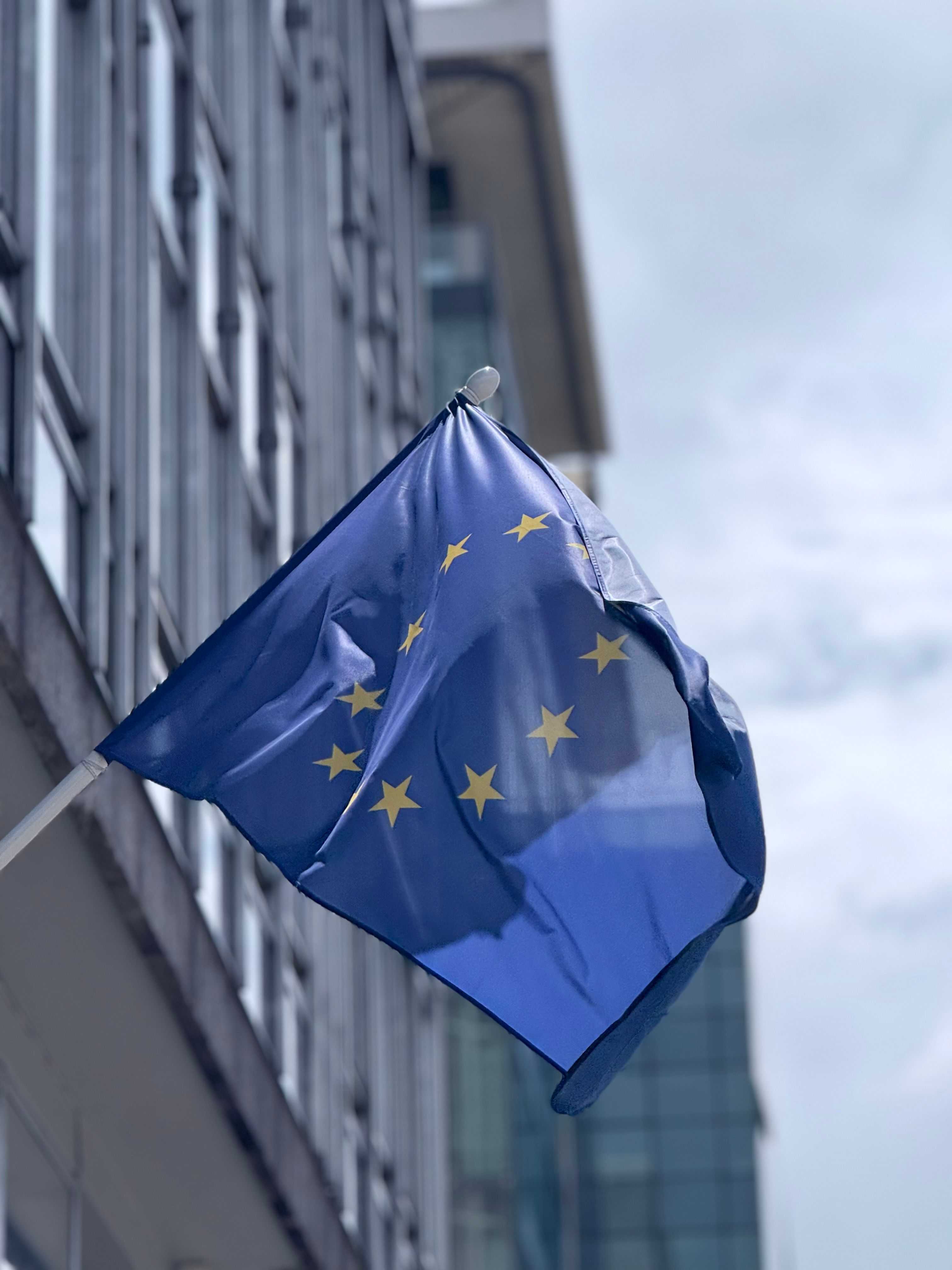 European Union Flag Waving Against Modern Building · Free Stock Photo