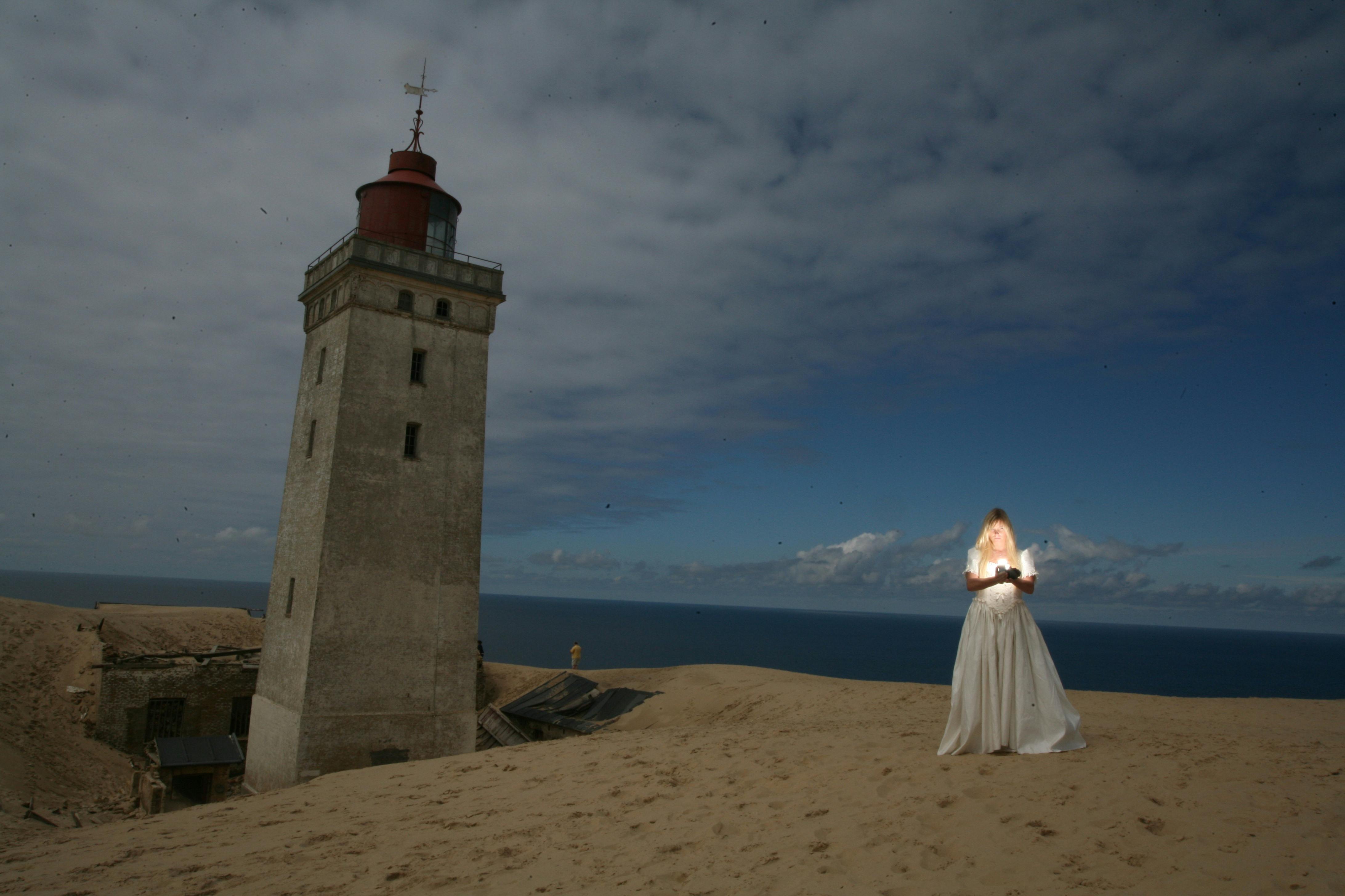 Woman Standing Near Gray Lighthouse · Free Stock Photo
