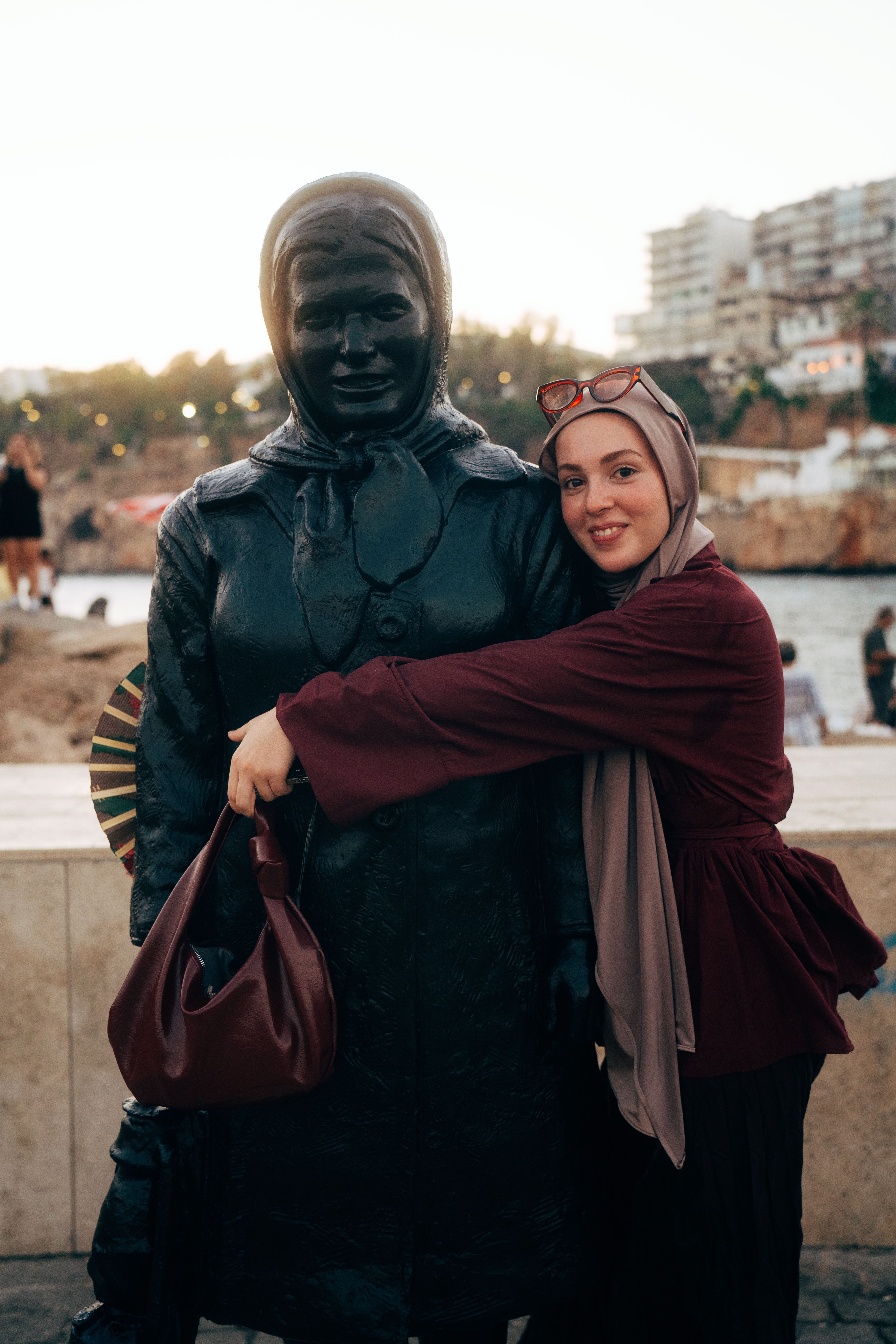 Woman Embracing Statue by Coastal Promenade · Free Stock Photo