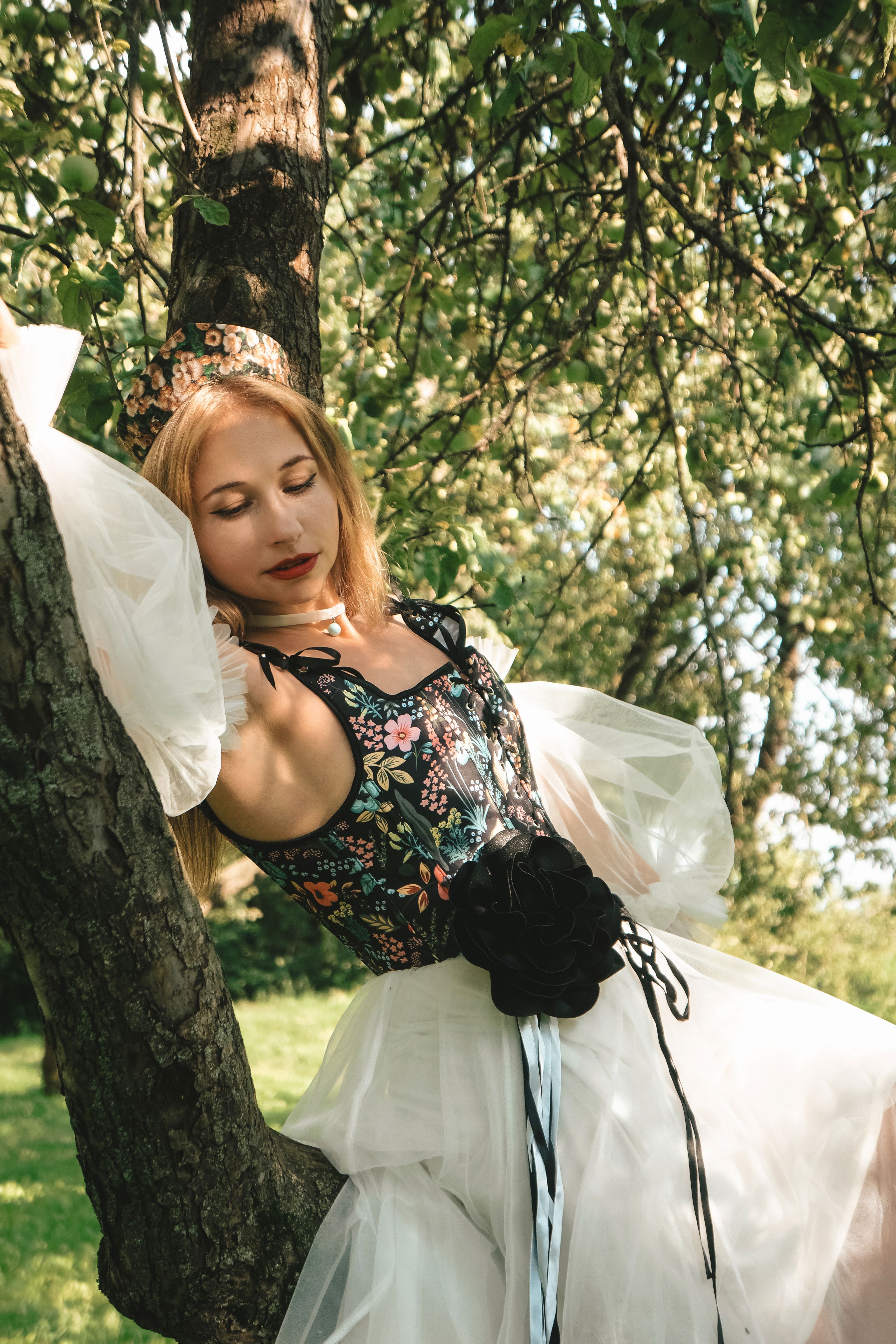 Enchanting Woman in Floral Dress Resting on Tree · Free Stock Photo