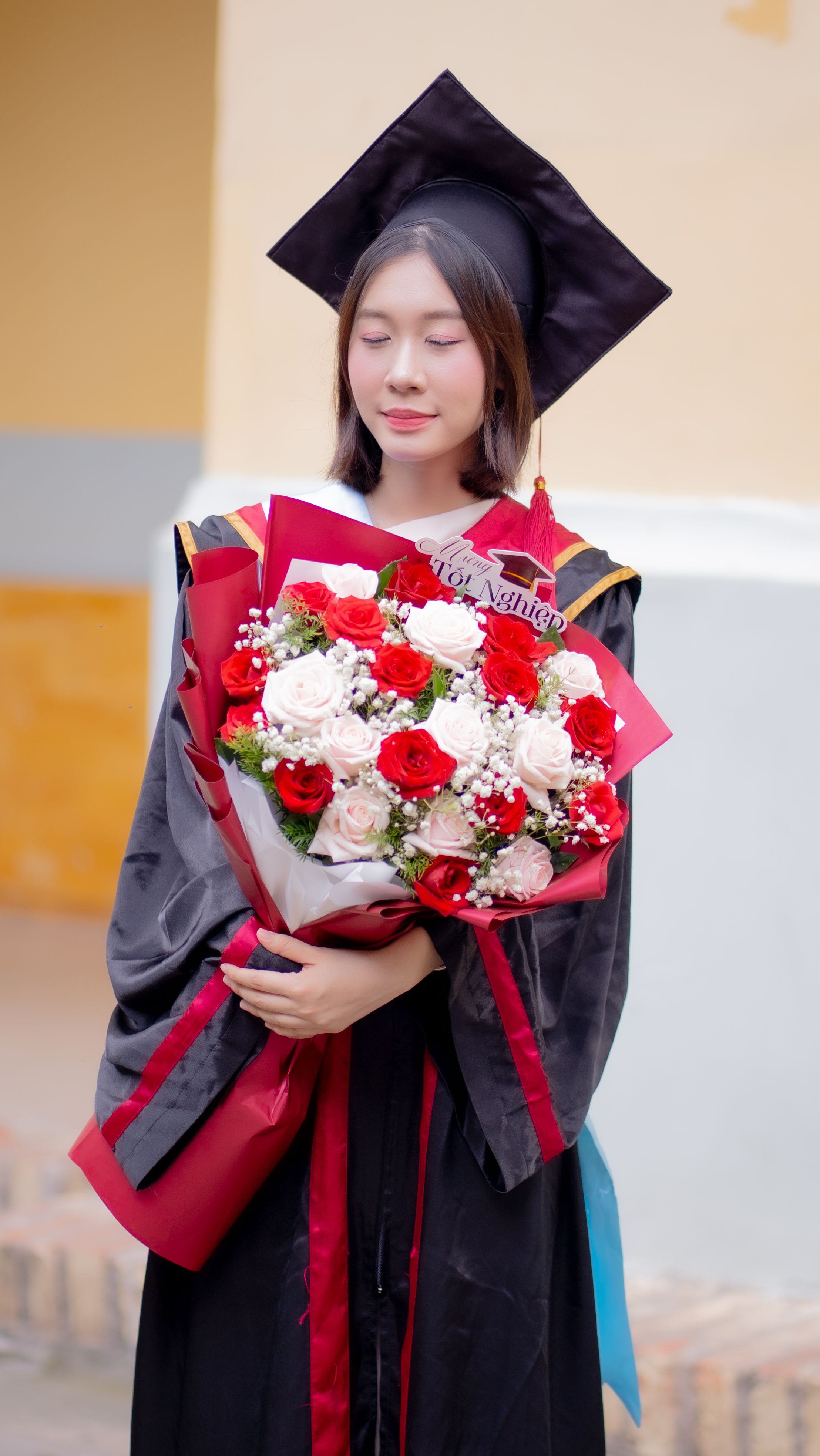 Young Graduate Holding Flower Bouquet in Cap and Gown · Free Stock Photo