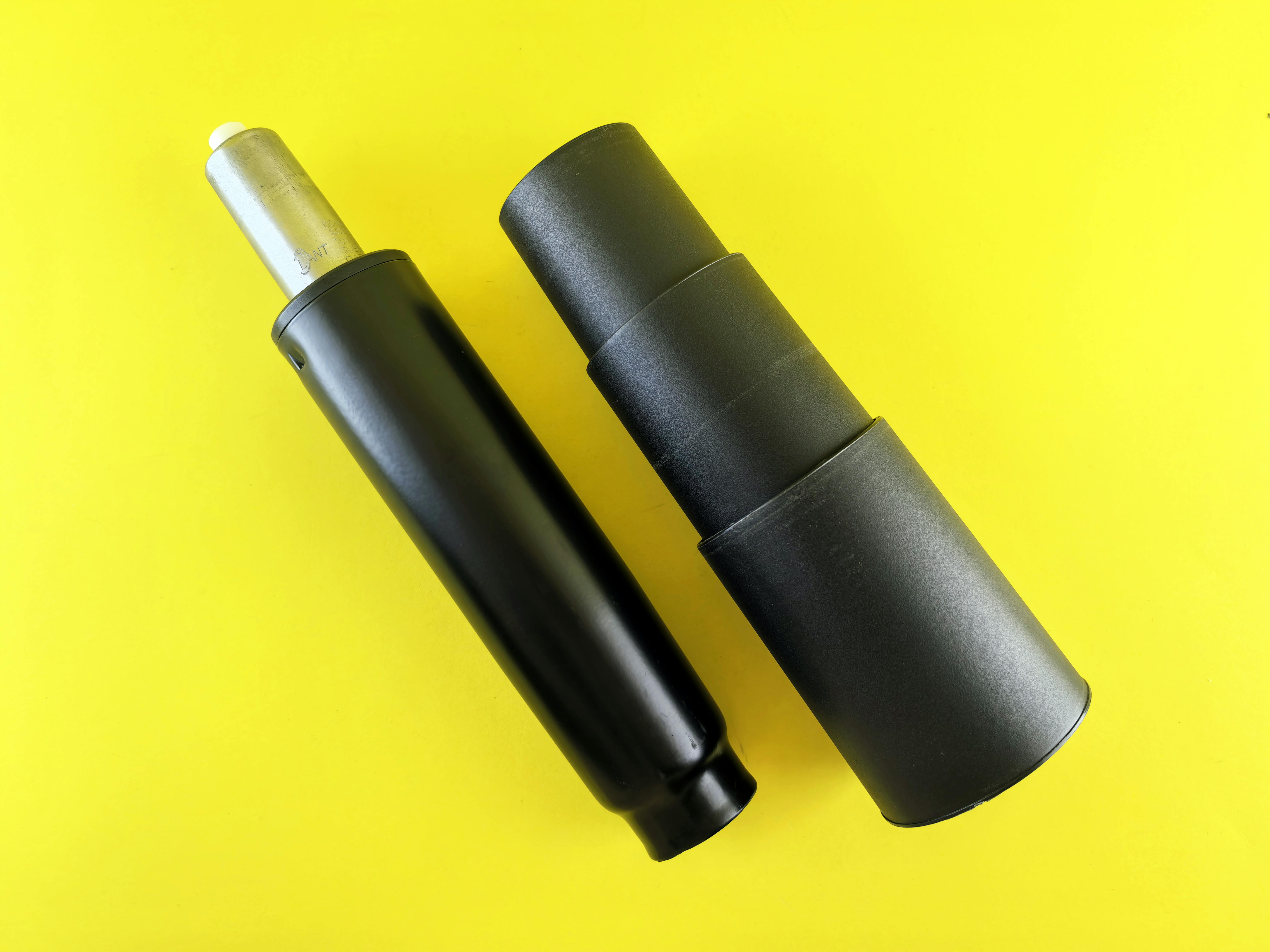 Zwarte Gasliftcilinders Op Gele Achtergrond · Gratis stockfoto