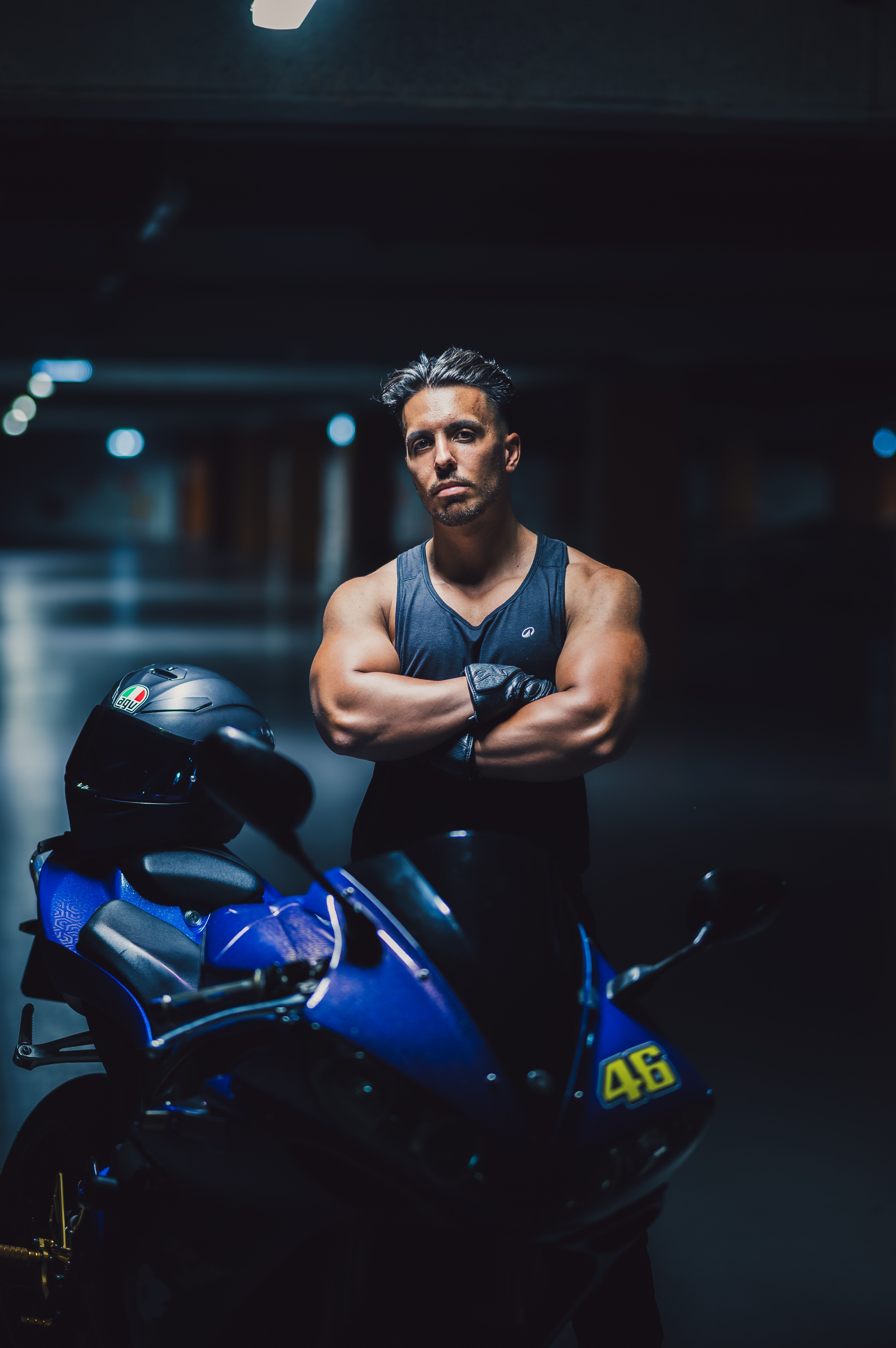 Man Posing with Motorcycle in Dimly Lit Garage · Free Stock Photo