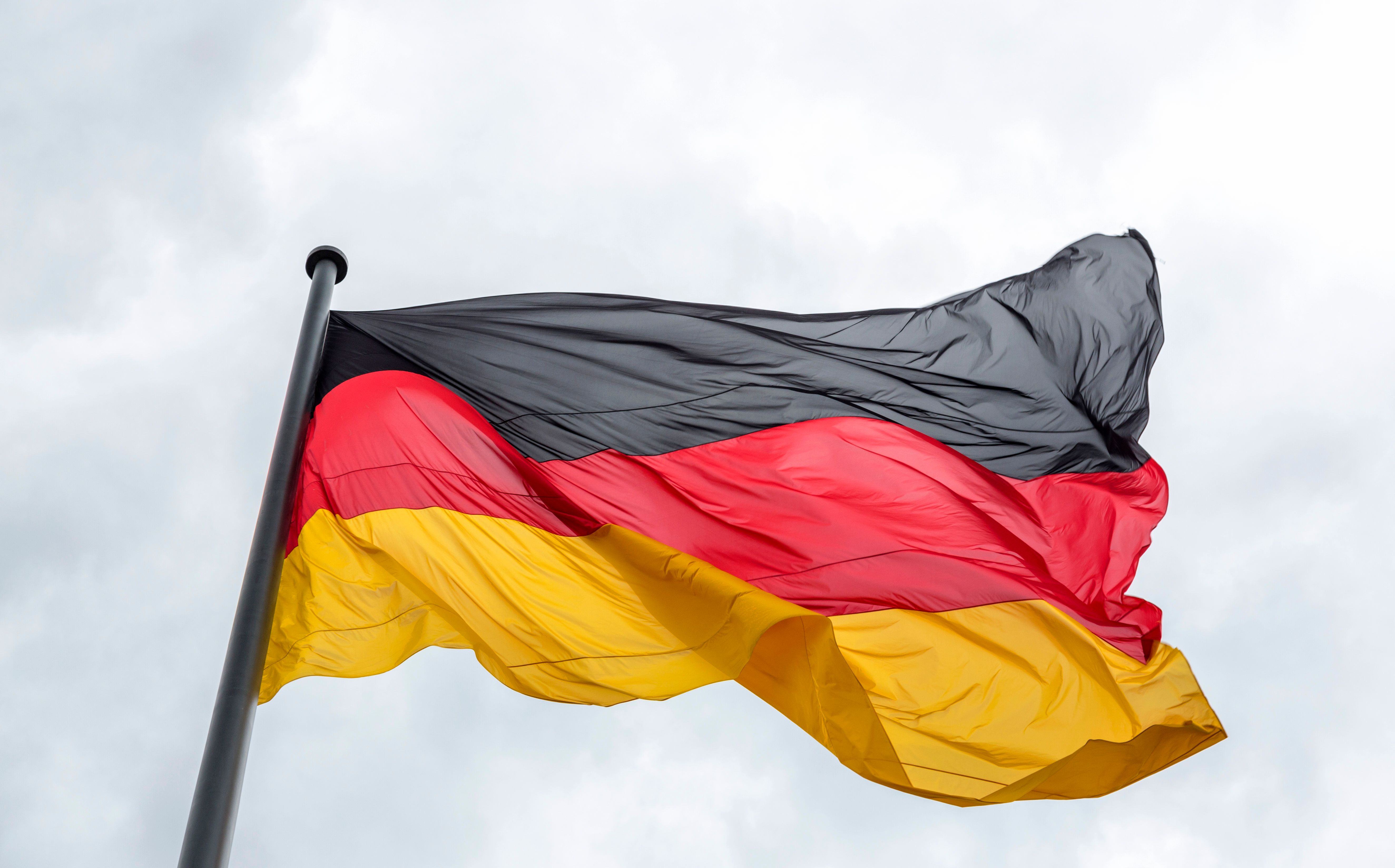 German Flag Waving Against Cloudy Sky · Free Stock Photo