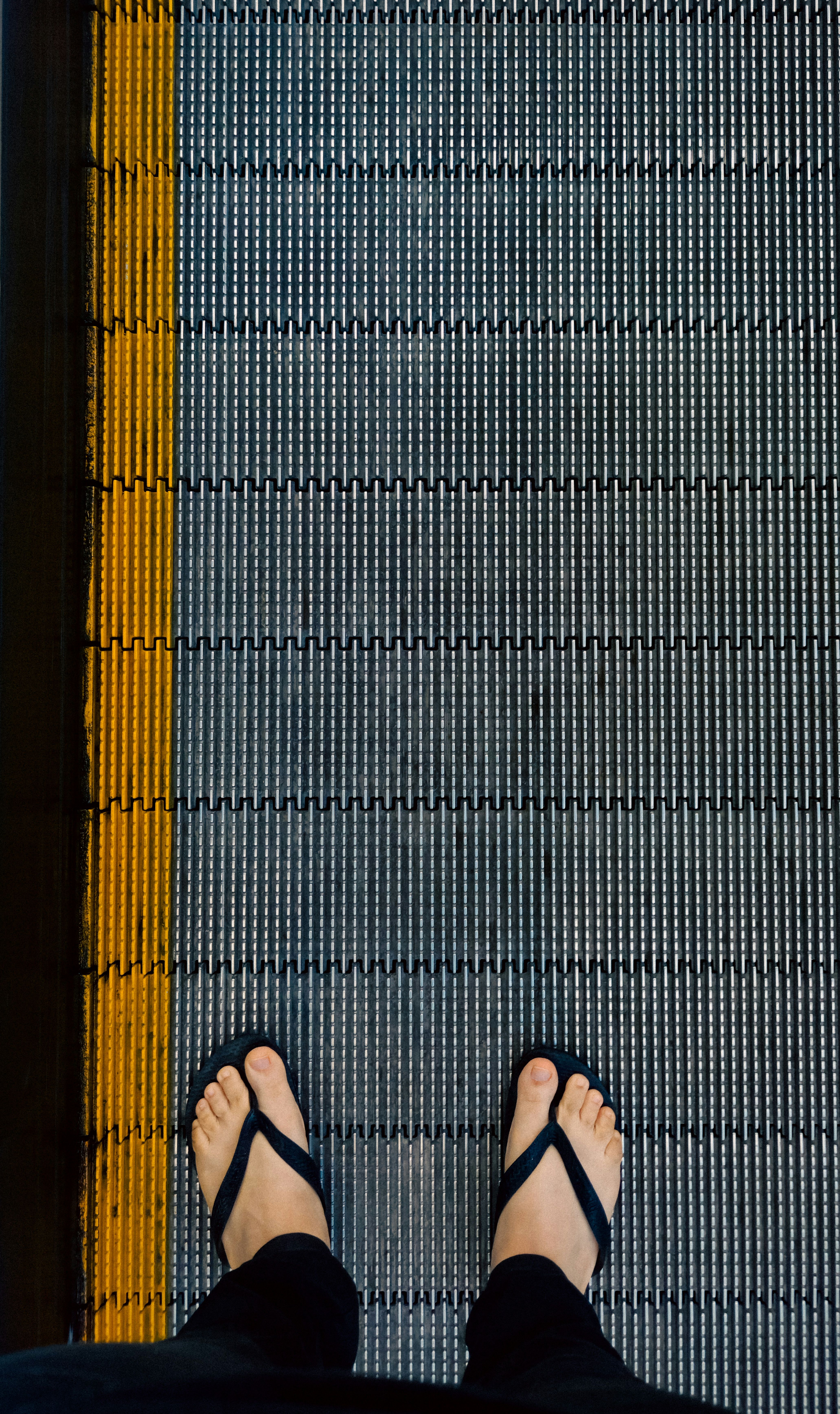 Person's Feet in Flip-Flops on Moving Walkway · Free Stock Photo