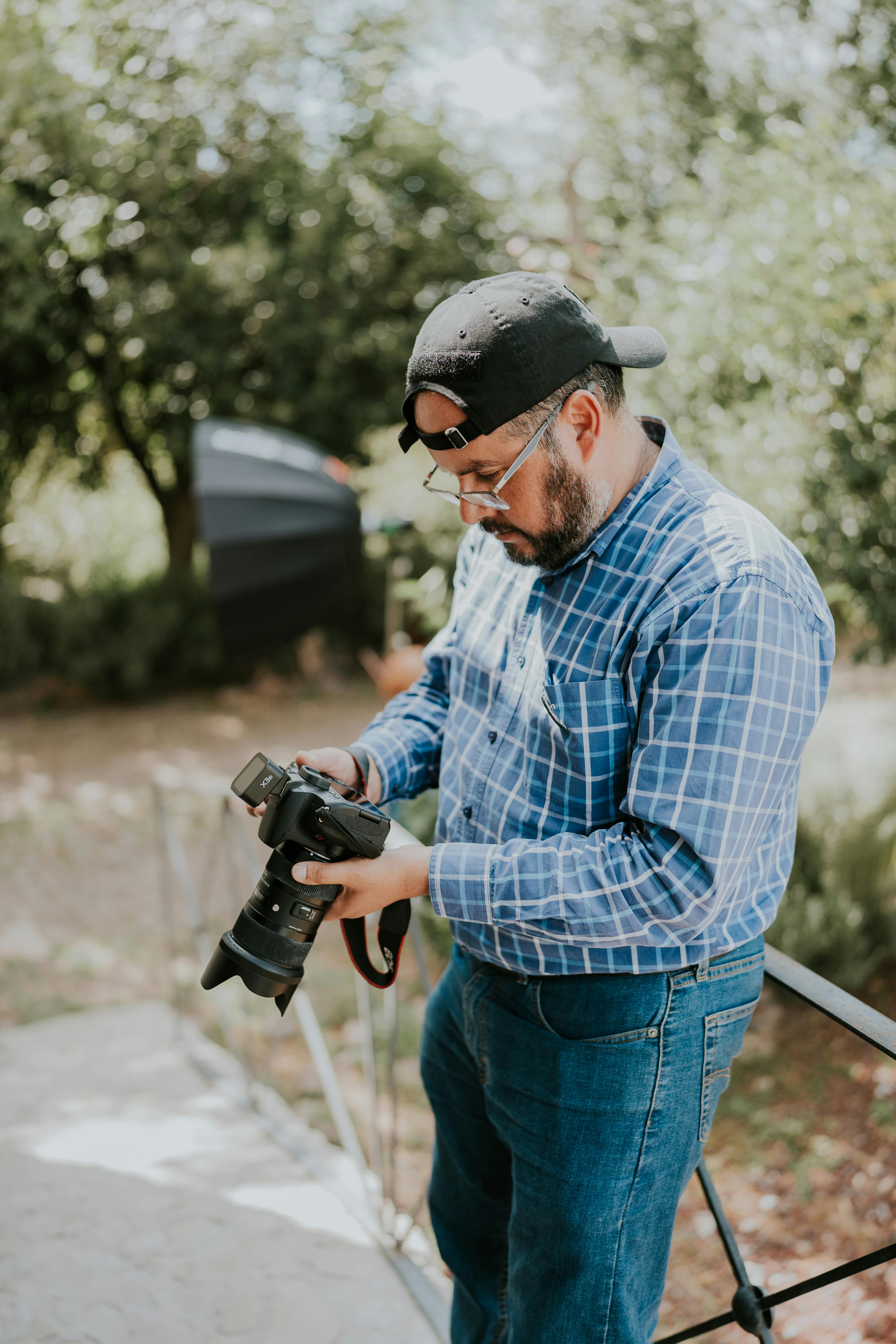 Photographer Reviewing Camera in Outdoor Setting · Free Stock Photo