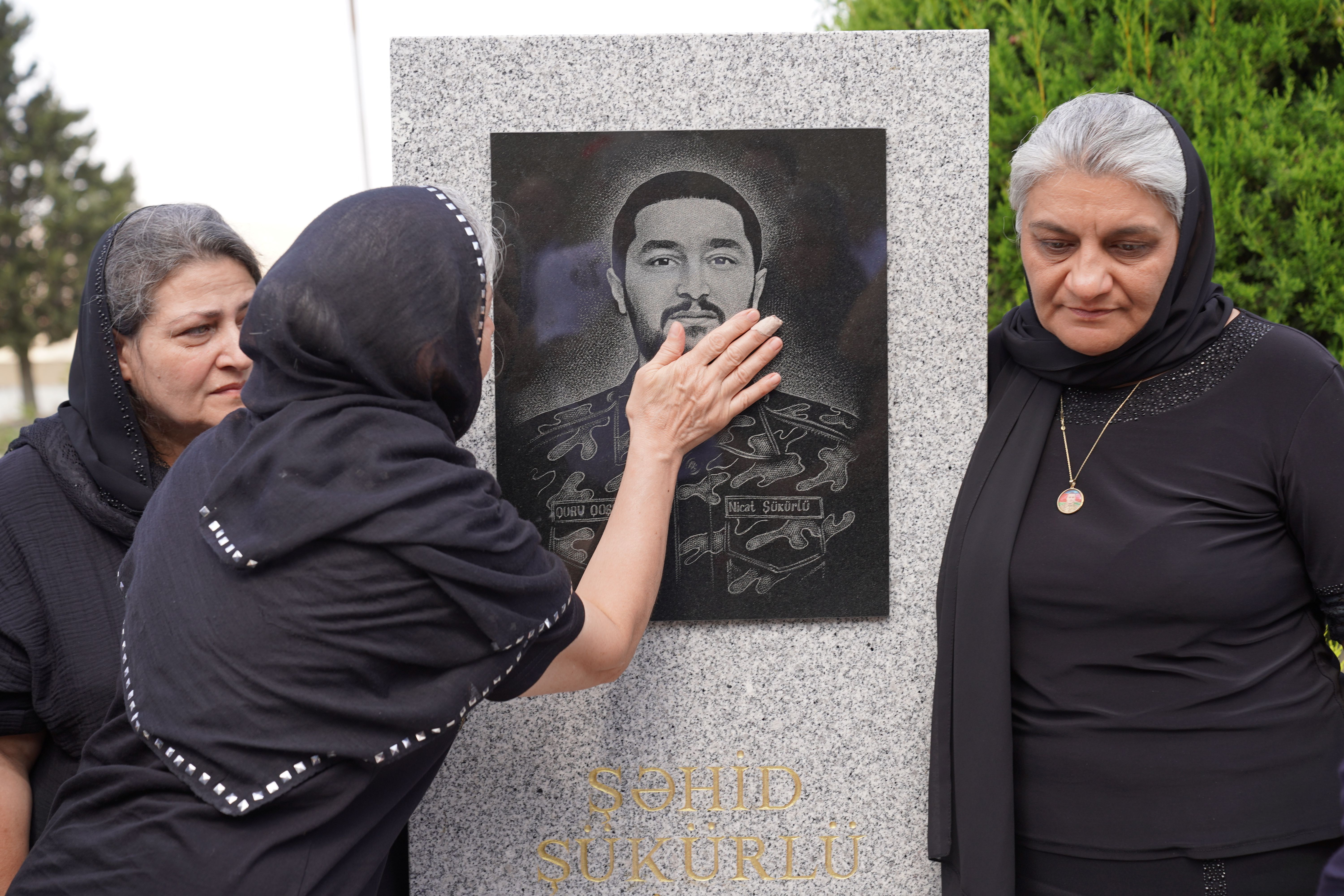 Women Grieving at a Memorial Stone Outdoors · Free Stock Photo