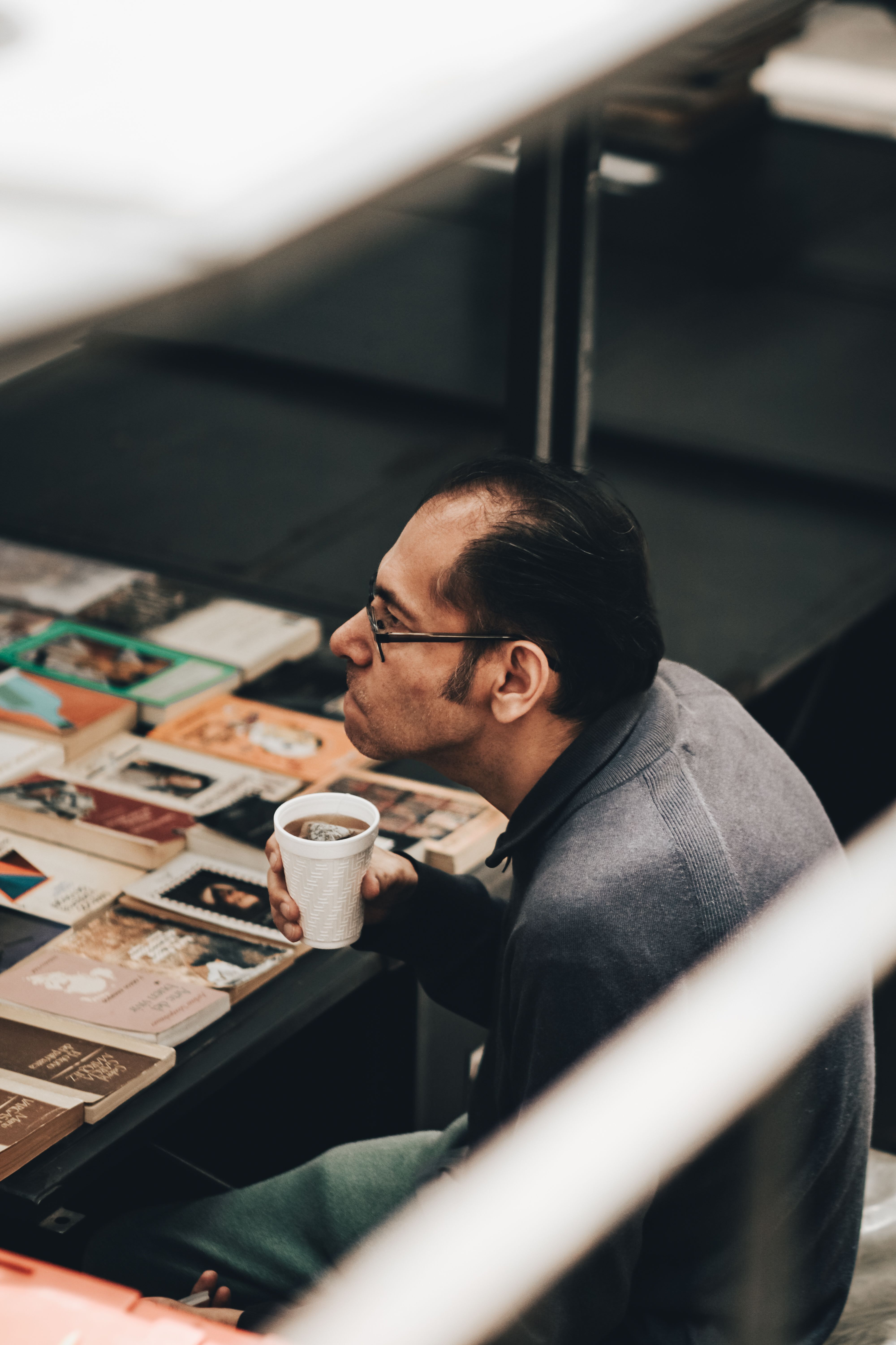 Man Sipping Coffee at Outdoor Book Market · Free Stock Photo