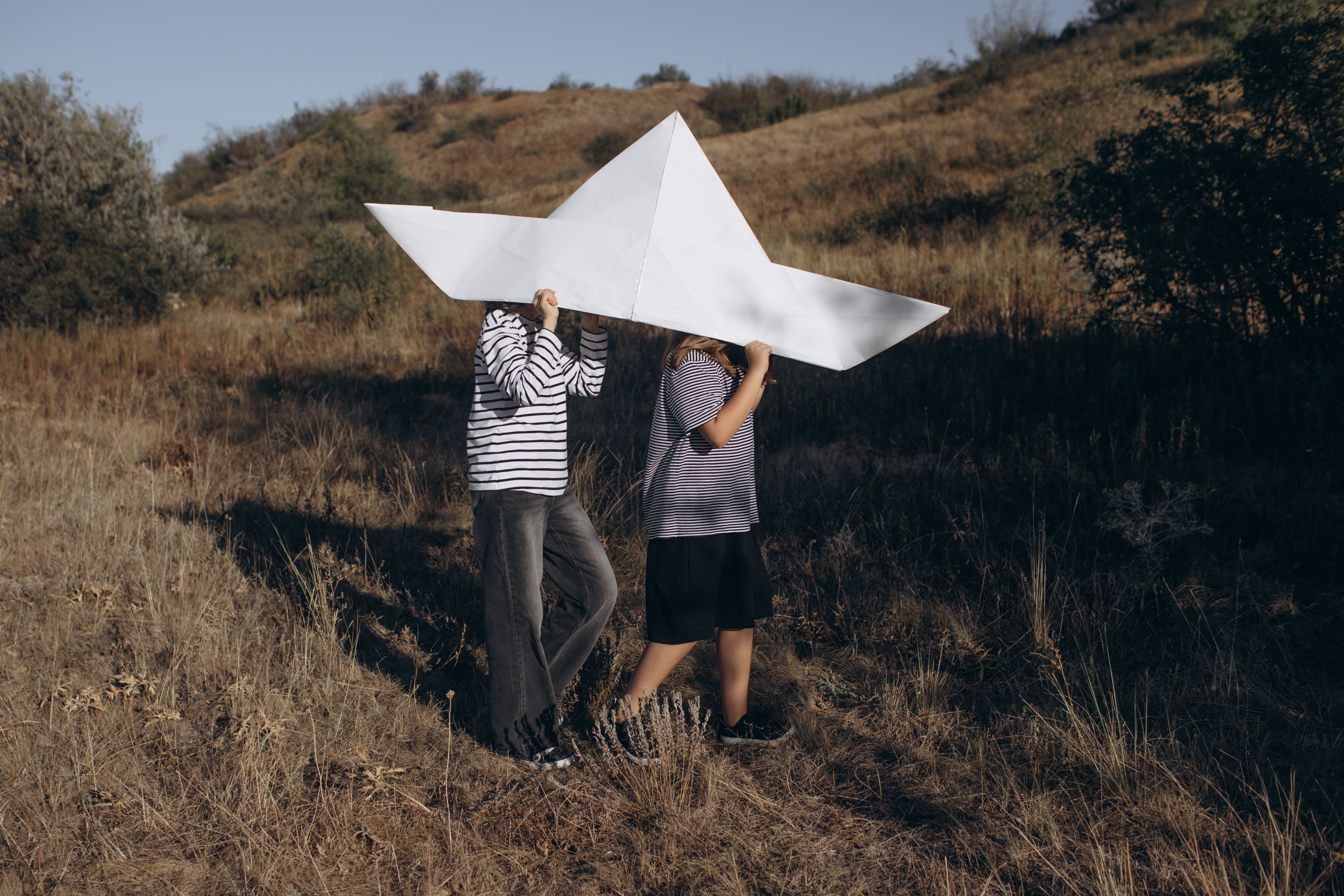 Children Playing with Giant Paper Airplane Outdoors · Free Stock Photo