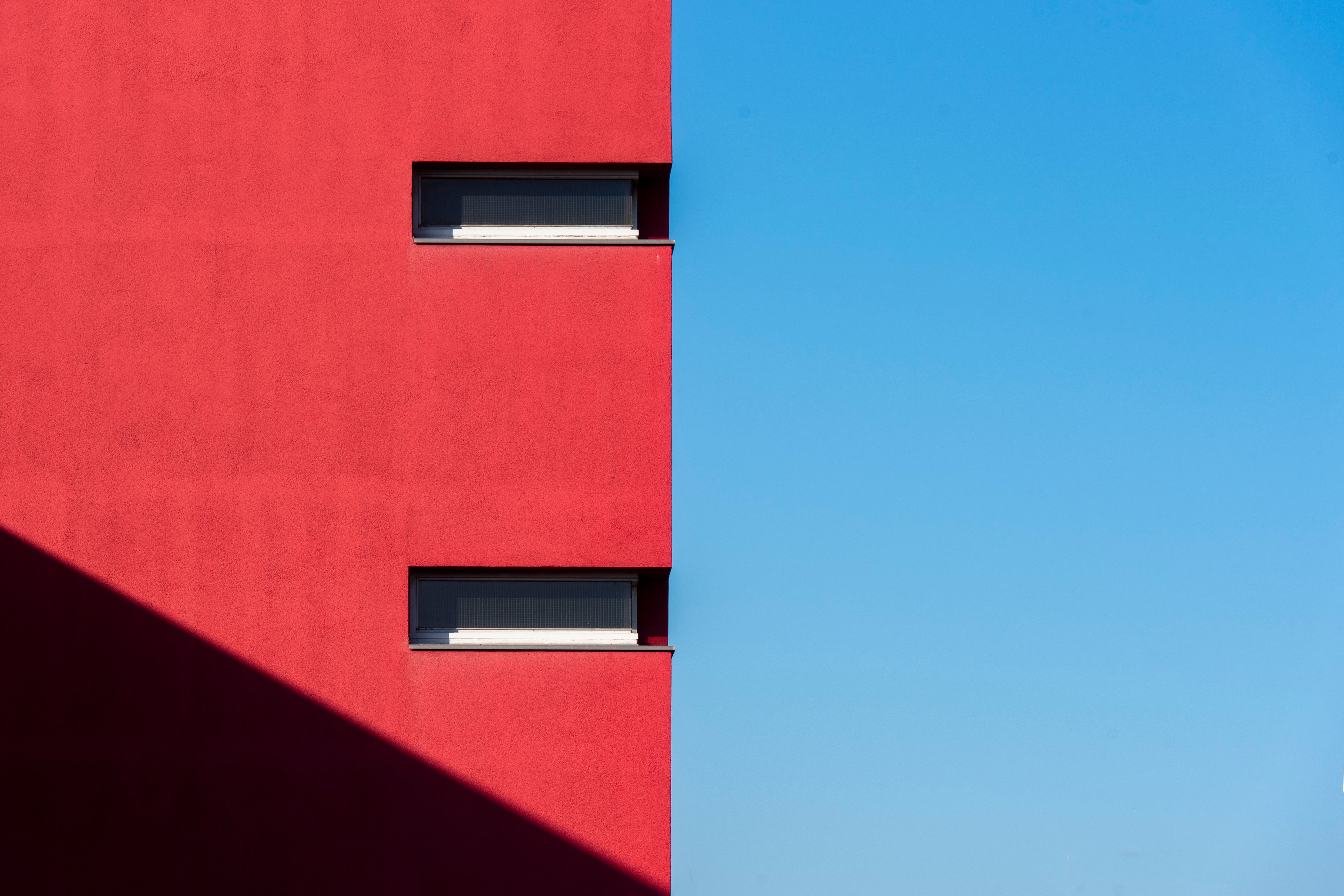 Bold Red Facade Against Clear Blue Sky · Free Stock Photo
