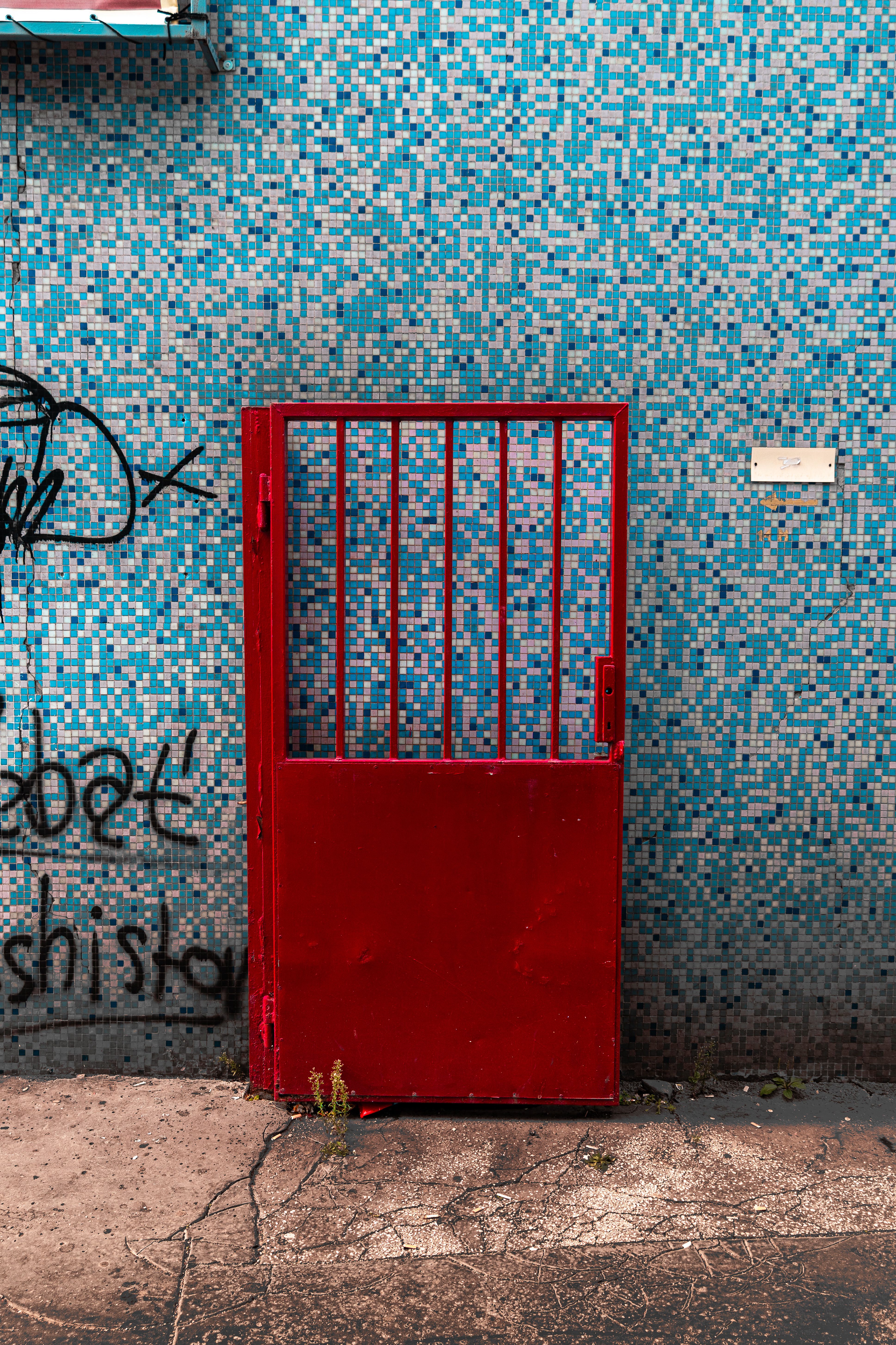 Vibrant Red Gate Against Blue Mosaic Wall · Free Stock Photo