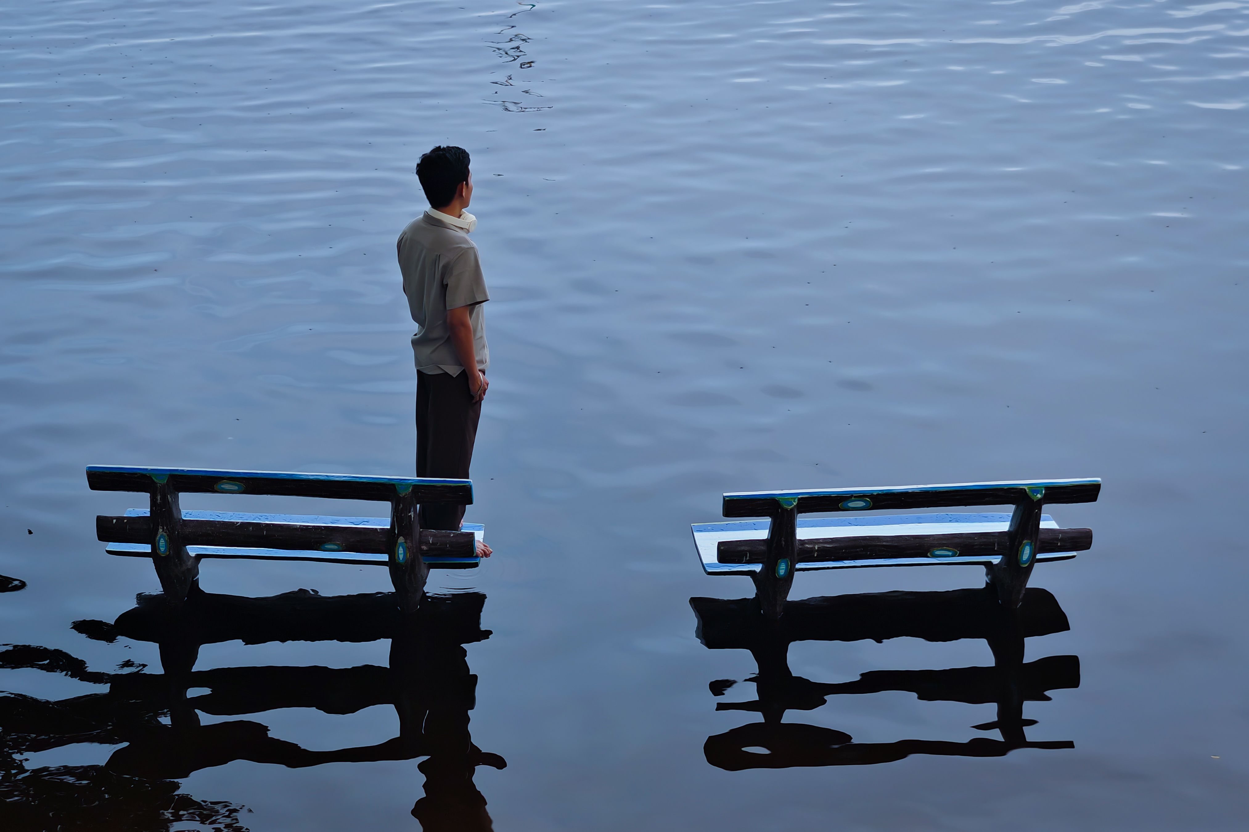 Man standing between benches in flooded area · Free Stock Photo