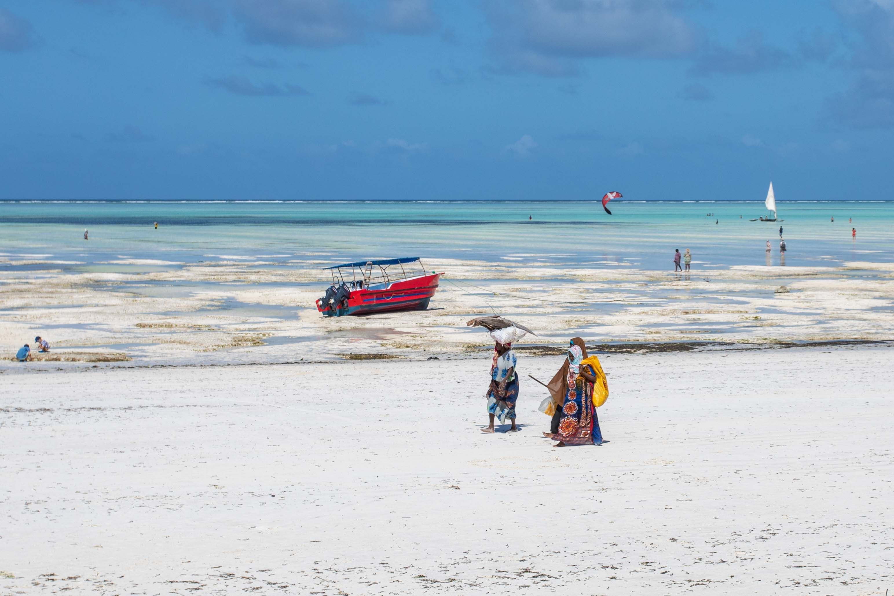 Vibrant African Beach Scene with Red Boat · Free Stock Photo
