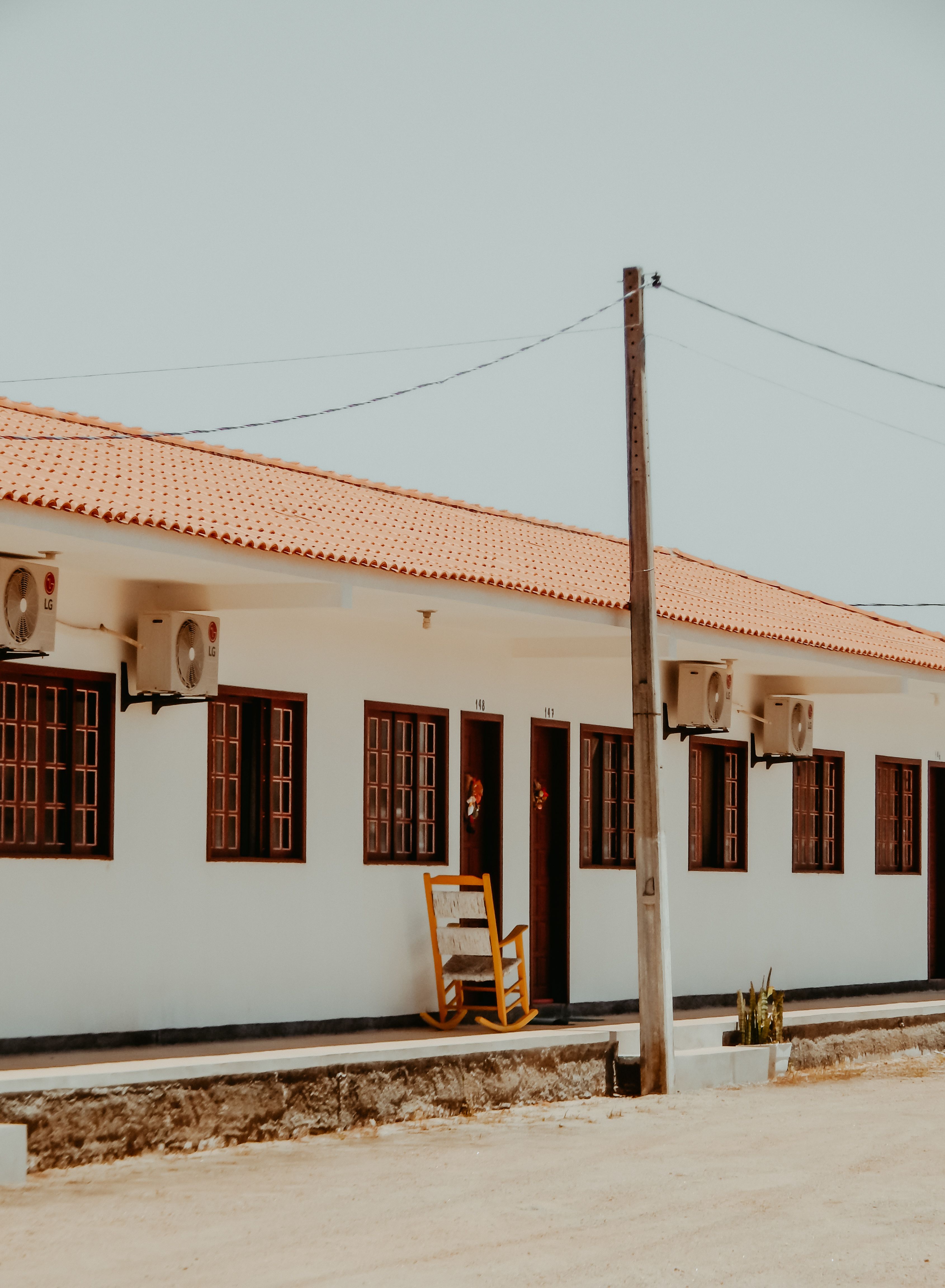 Sunlit Motel Exterior with Rocking Chair · Free Stock Photo