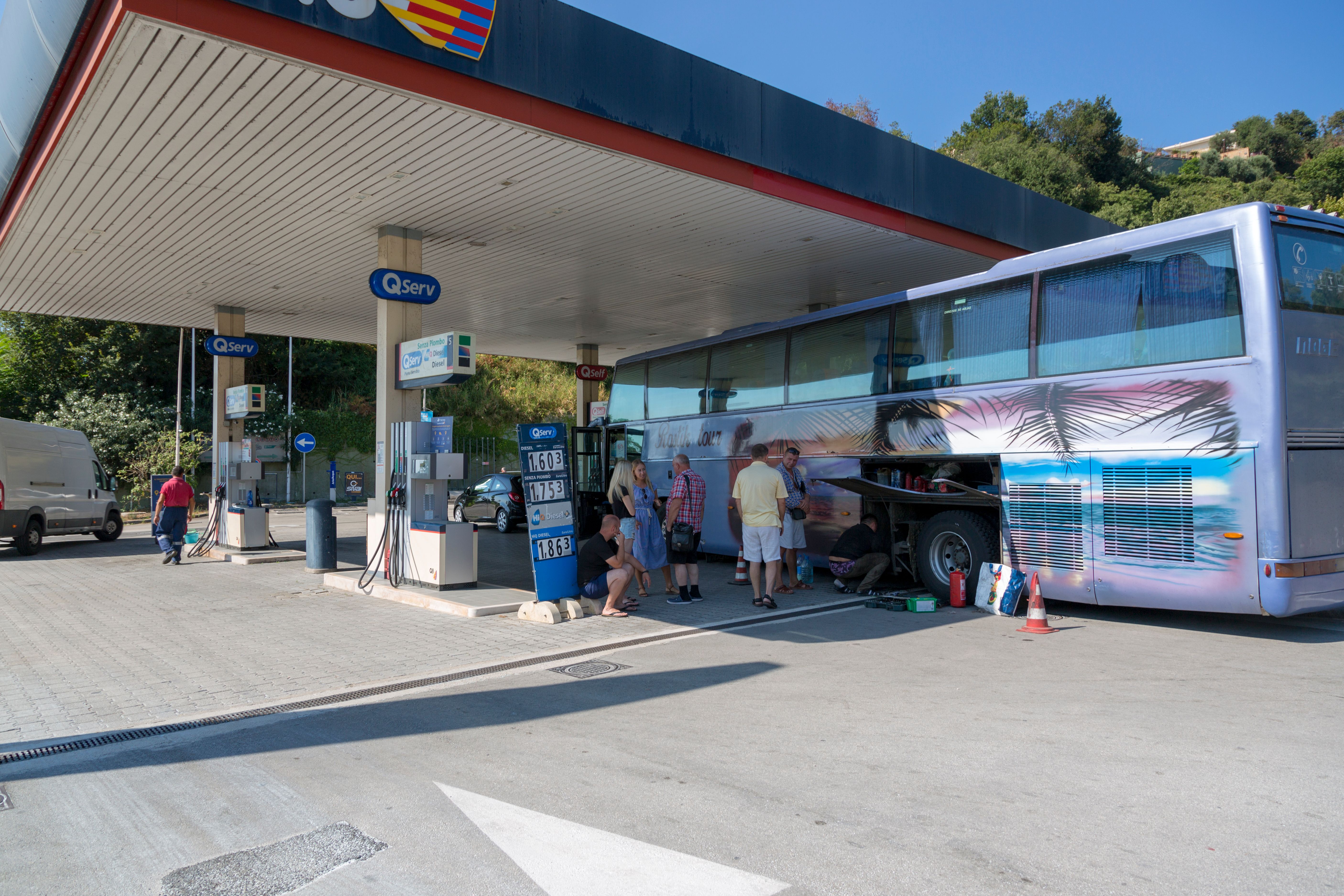 Tour Bus at Gas Station with People Resting Outdoors · Free Stock Photo