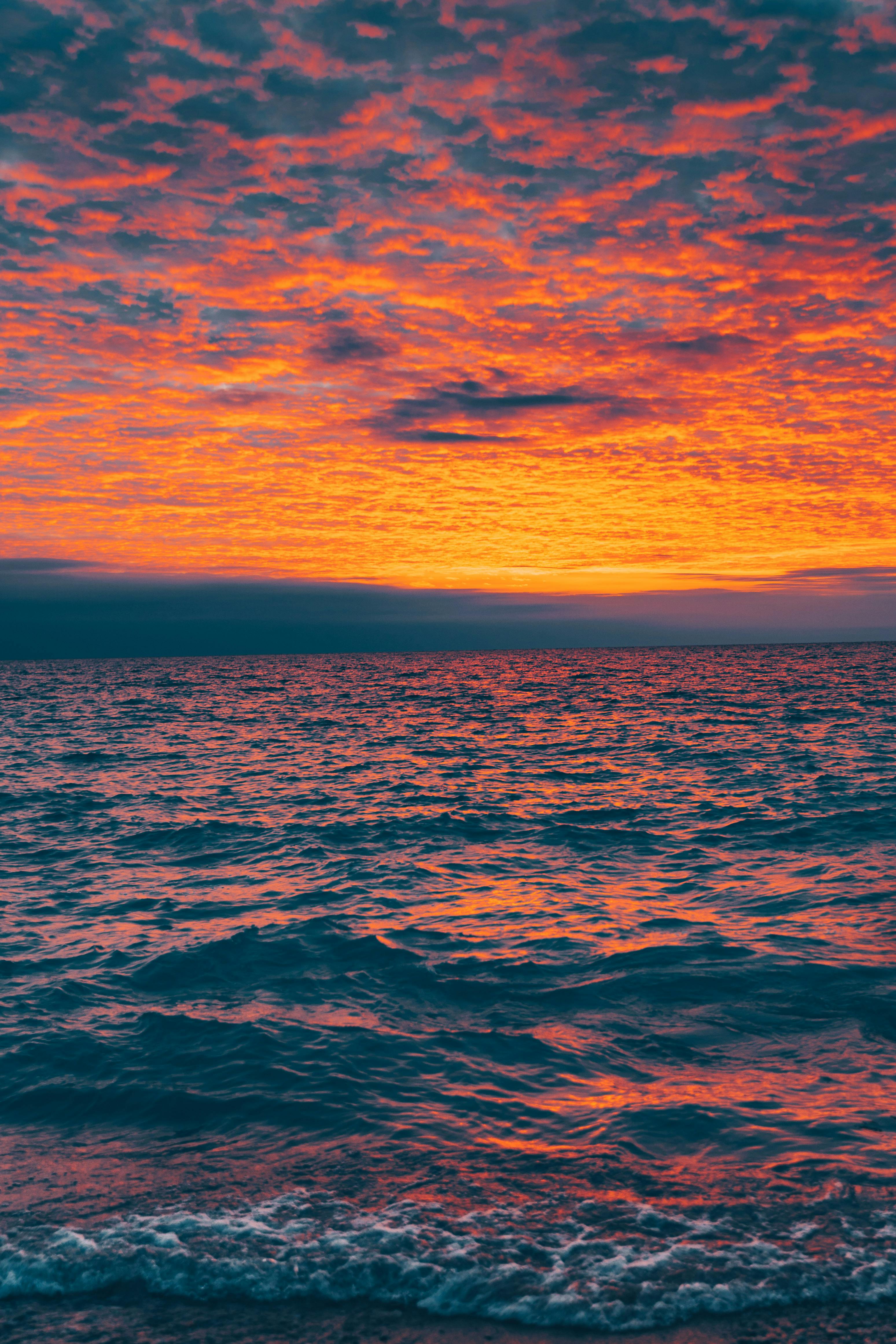 Bright sunset over rippling ocean on cloudy day · Free Stock Photo