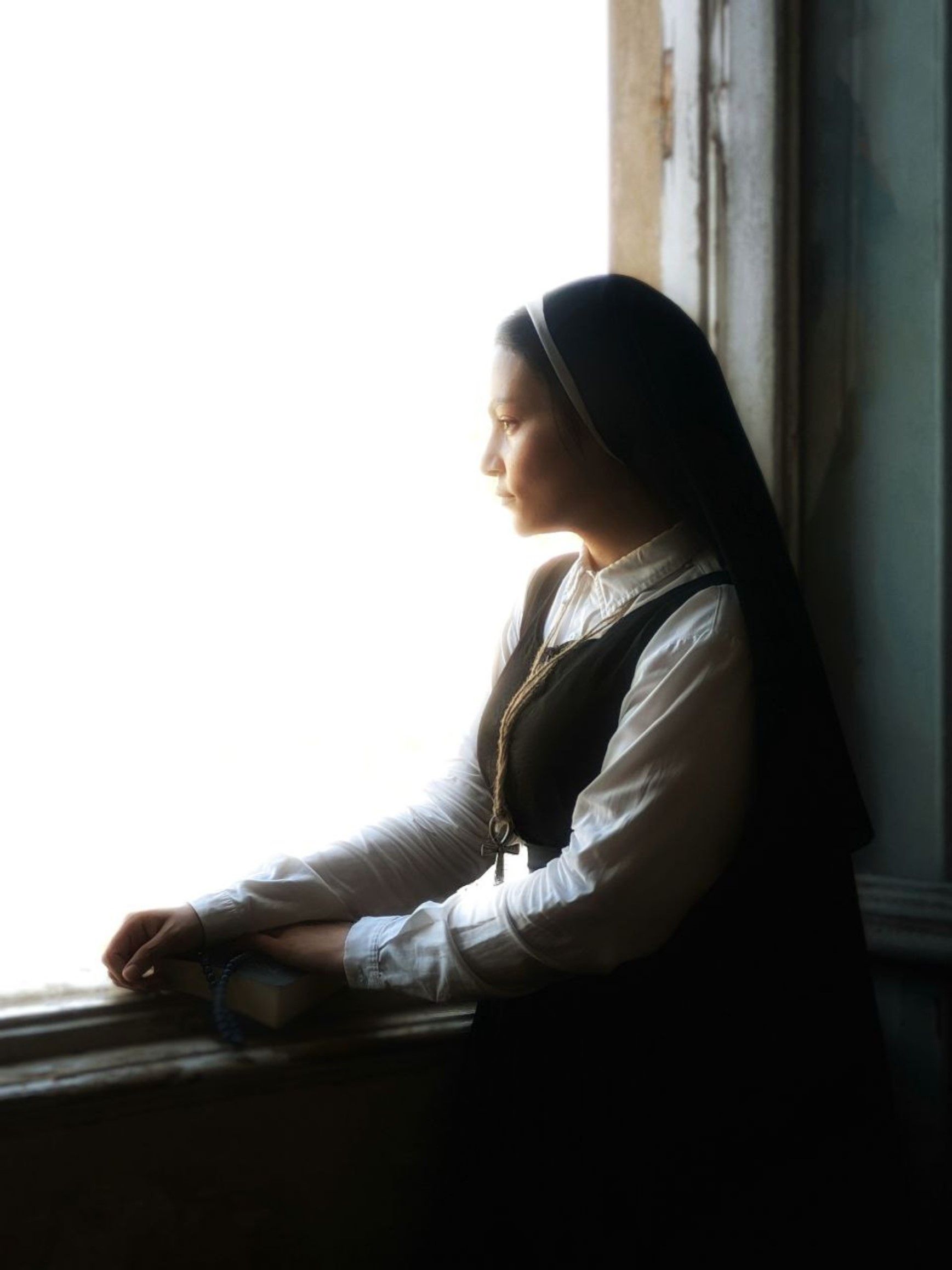 Contemplative Moment of a Nun by a Sunlit Window · Free Stock Photo