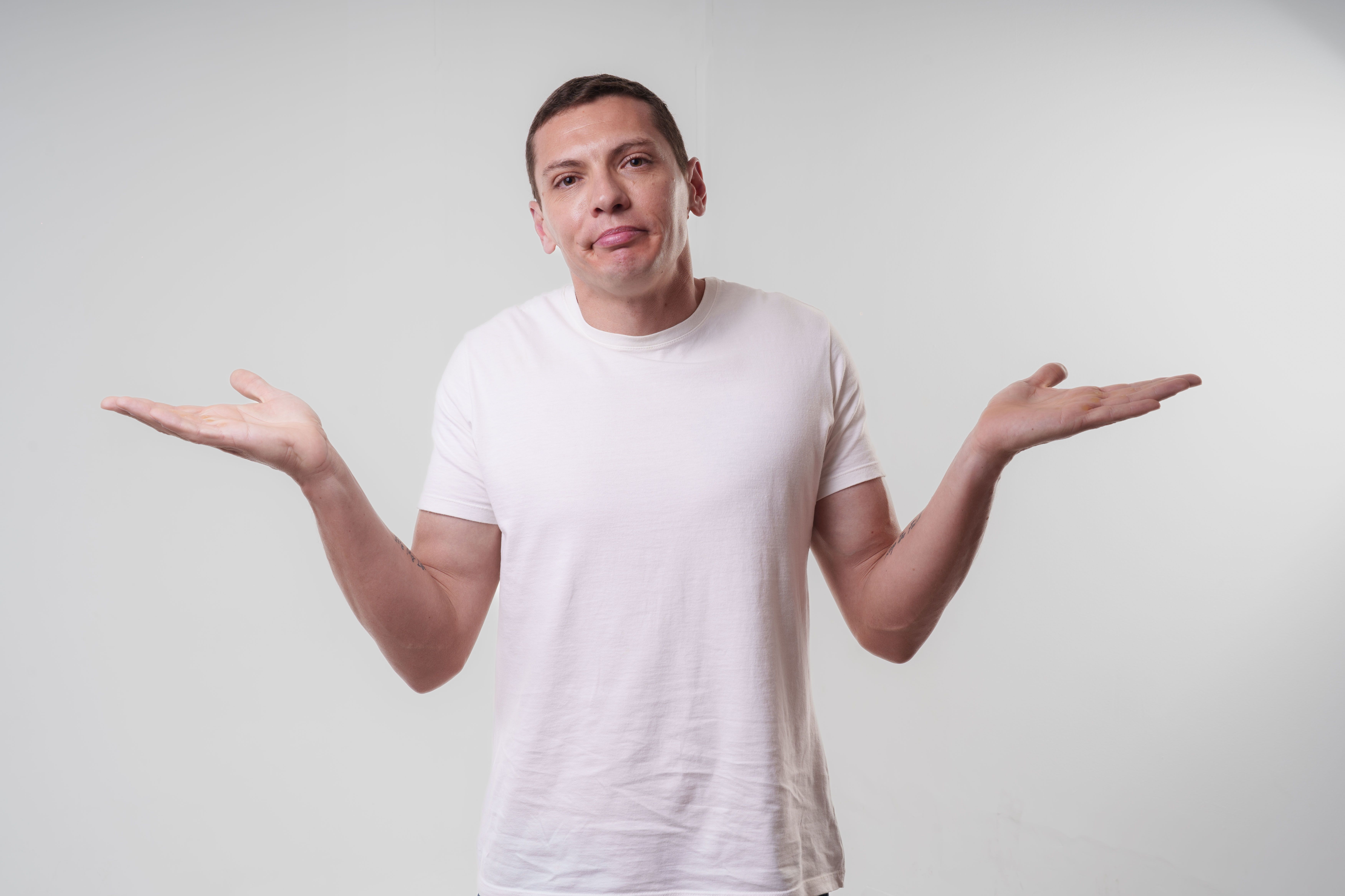Man Shrugging in White Shirt on Neutral Background · Free Stock Photo