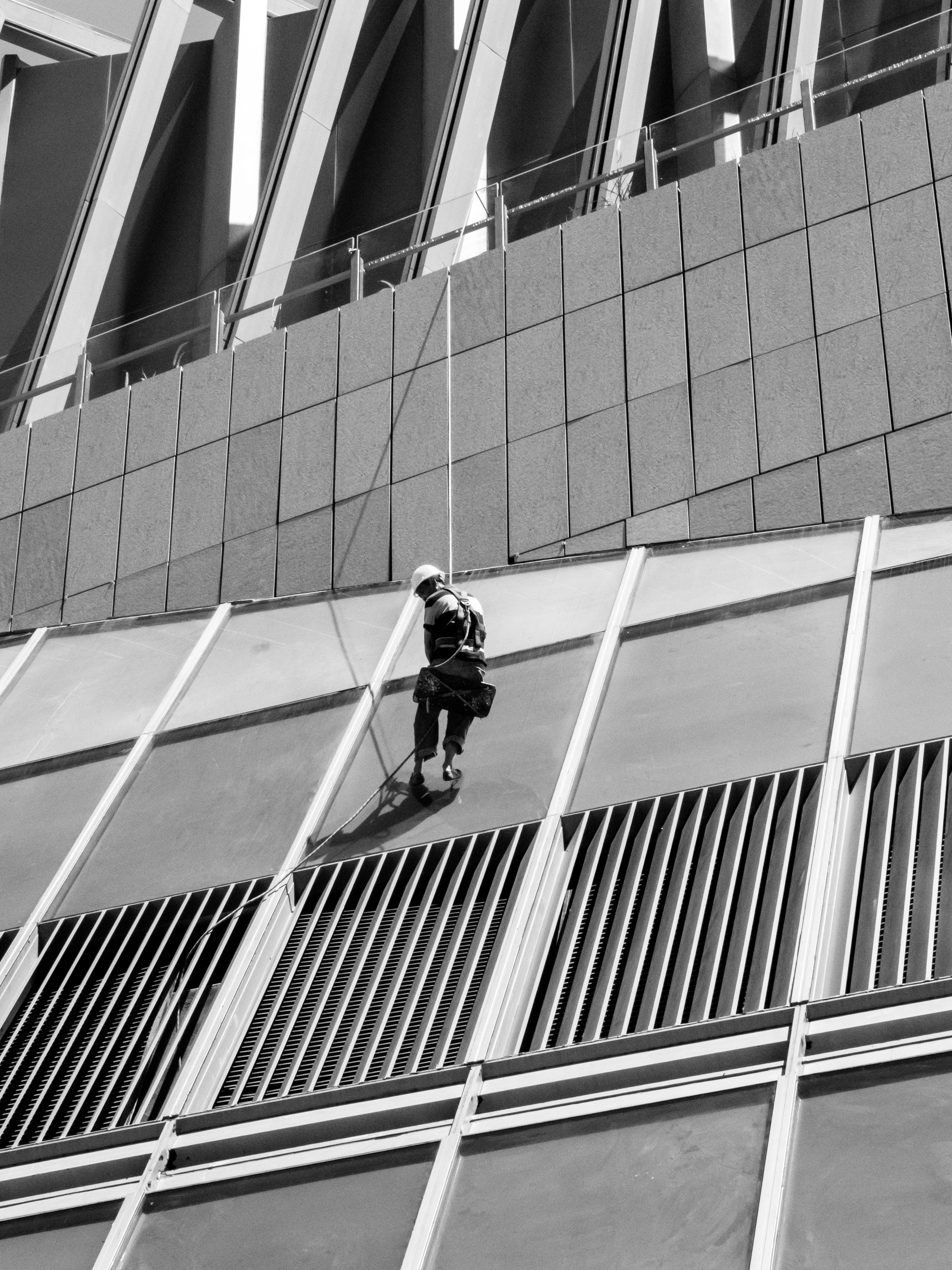 Rooftop Worker Scaling Tall Building Facade · Free Stock Photo
