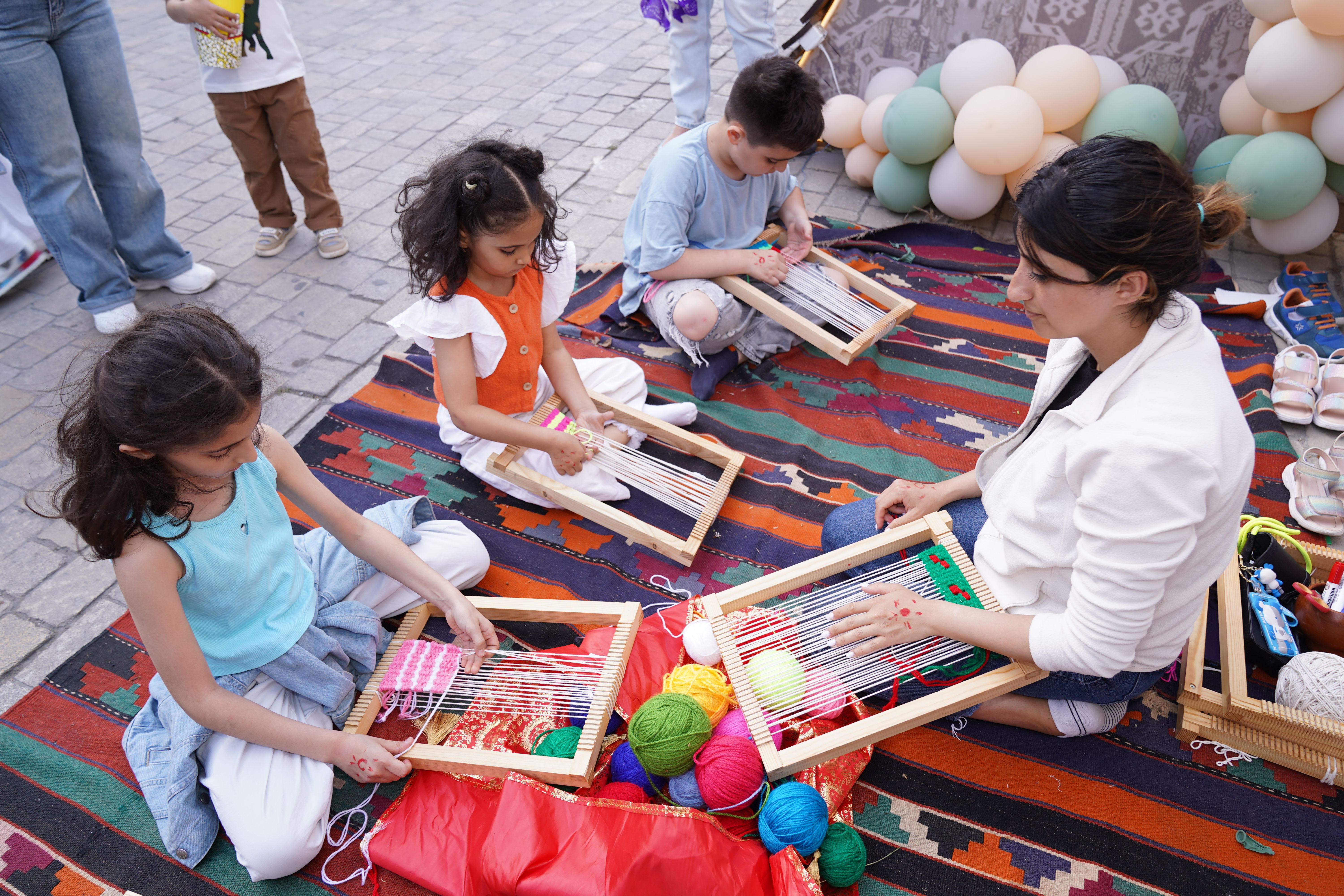 Children and Woman Weaving Outdoors on Colorful Mat · Free Stock Photo