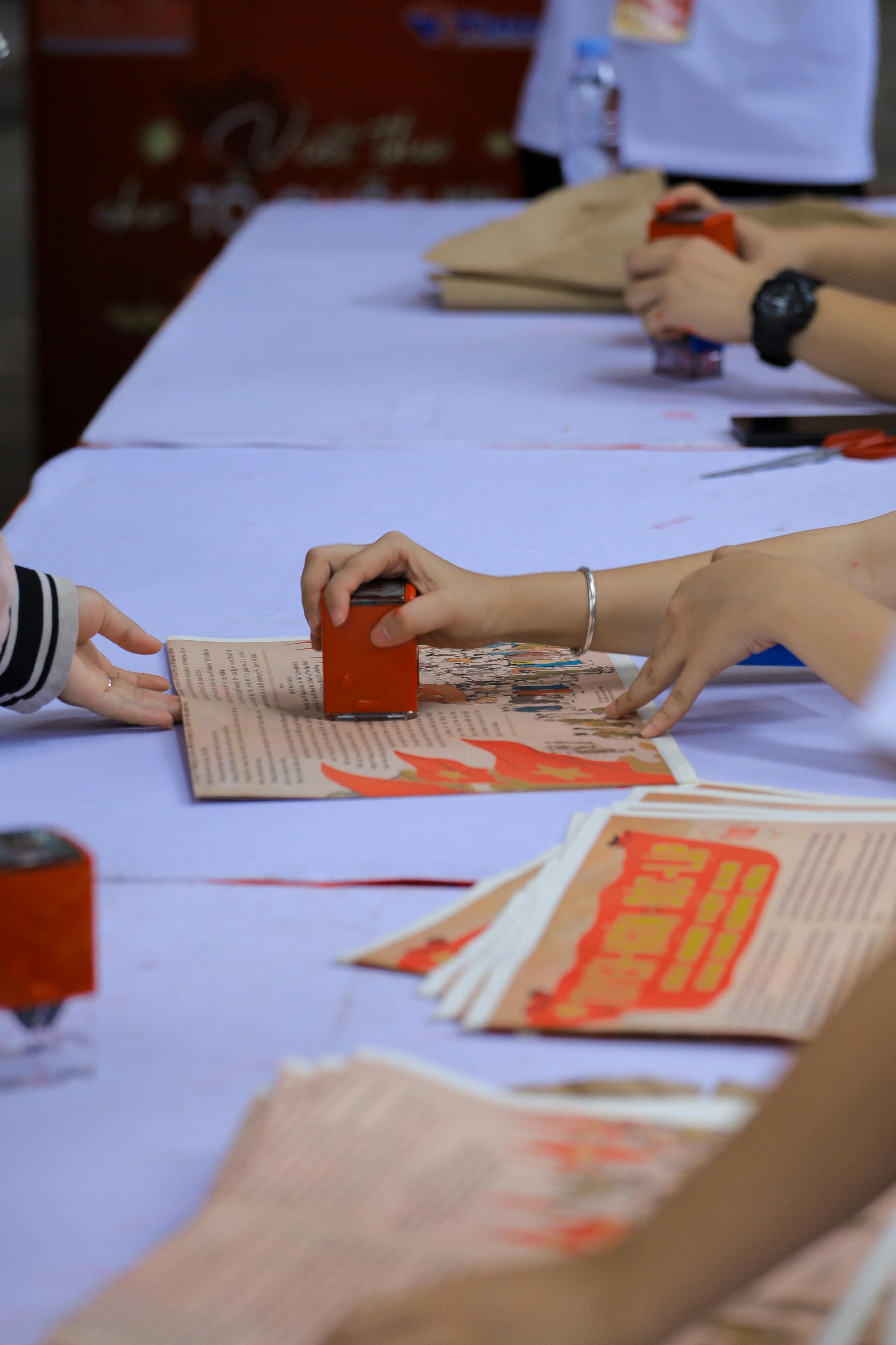 Free People hand-stamping red prints on paper sheets during a cultural ...
