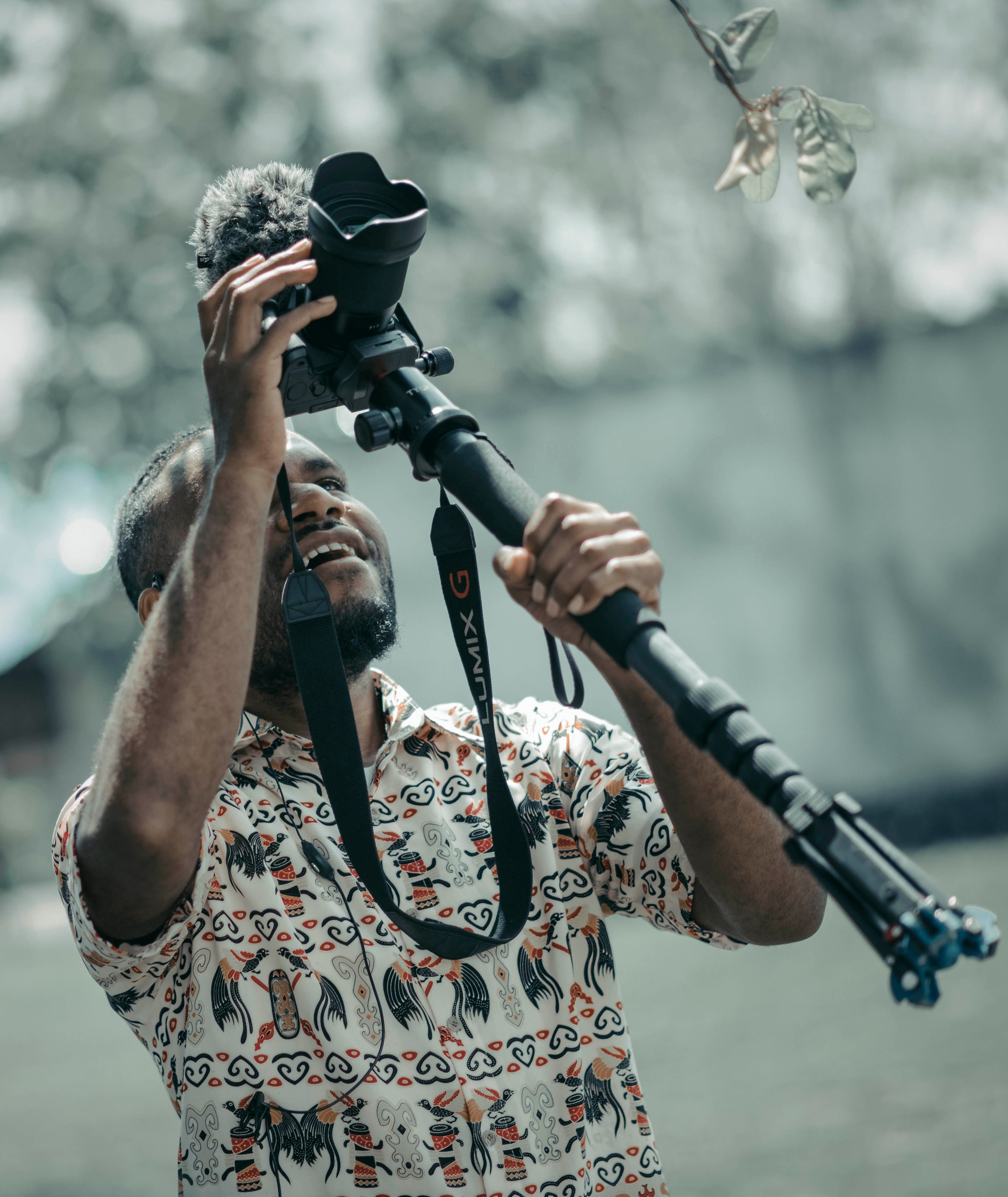 Man with Camera on Tripod Capturing Scene Outdoors · Free Stock Photo