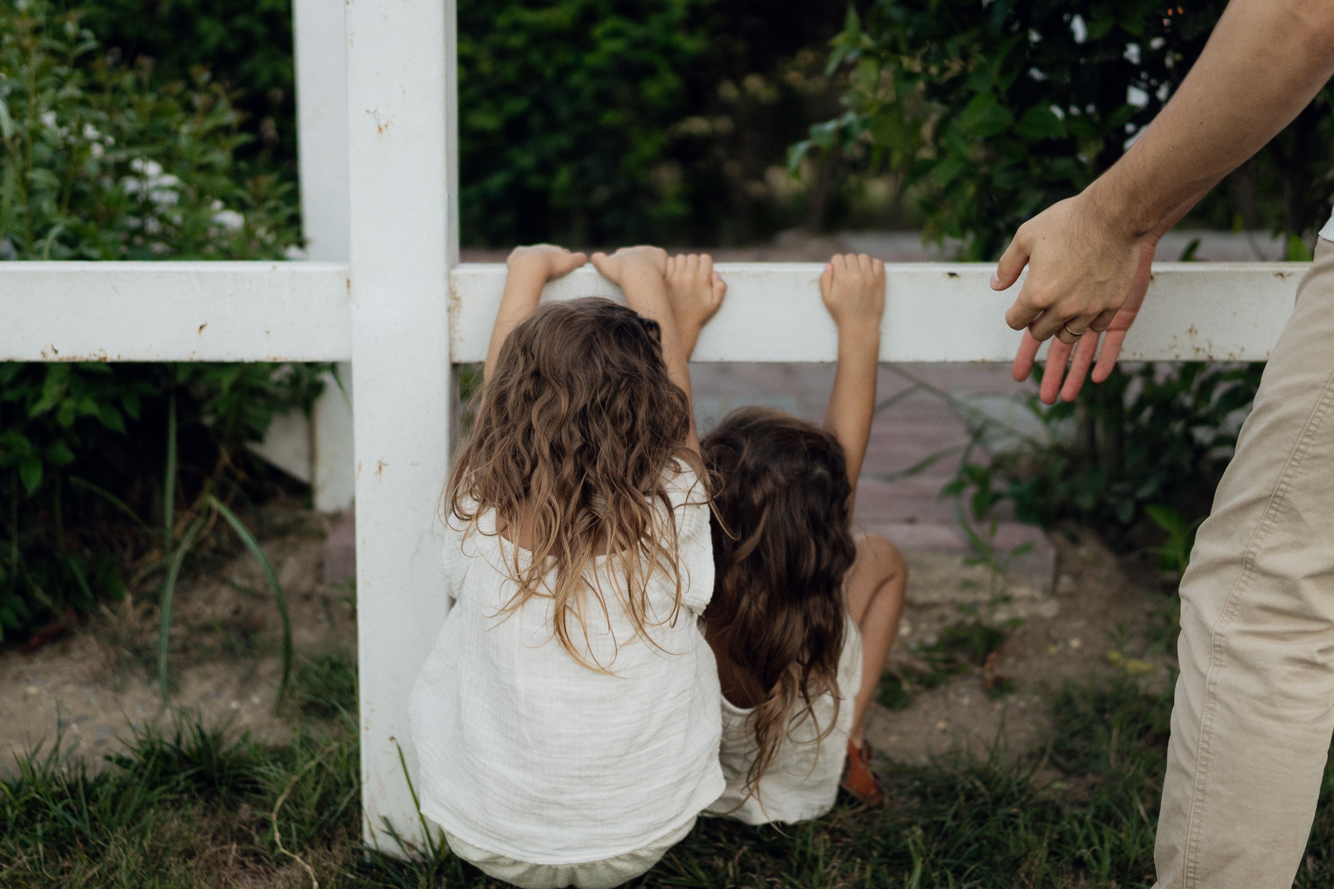 Children Playing by a White Wooden Fence Outdoors · Free Stock Photo