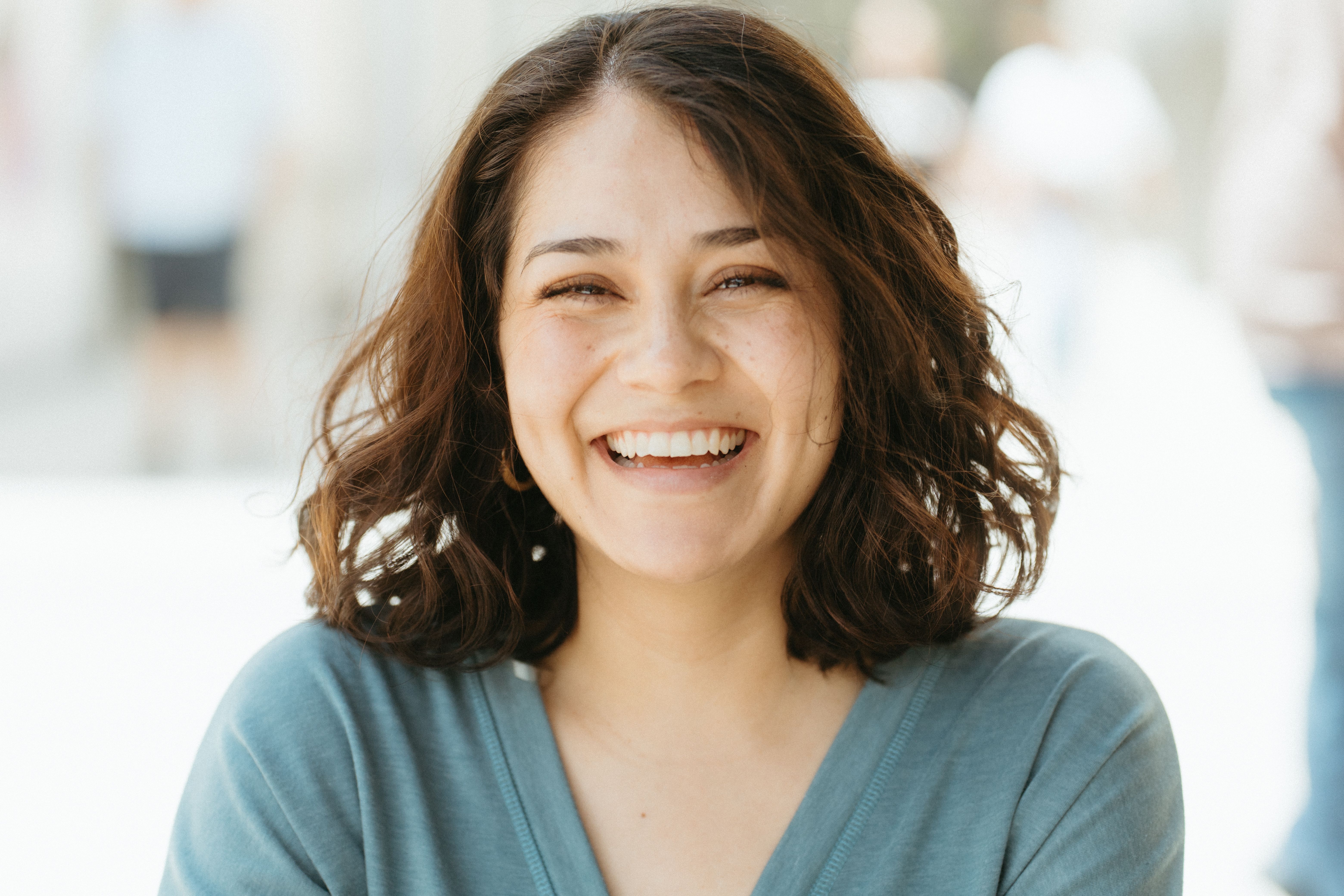 Cheerful Woman Smiling Outdoors in Bright Light · Free Stock Photo