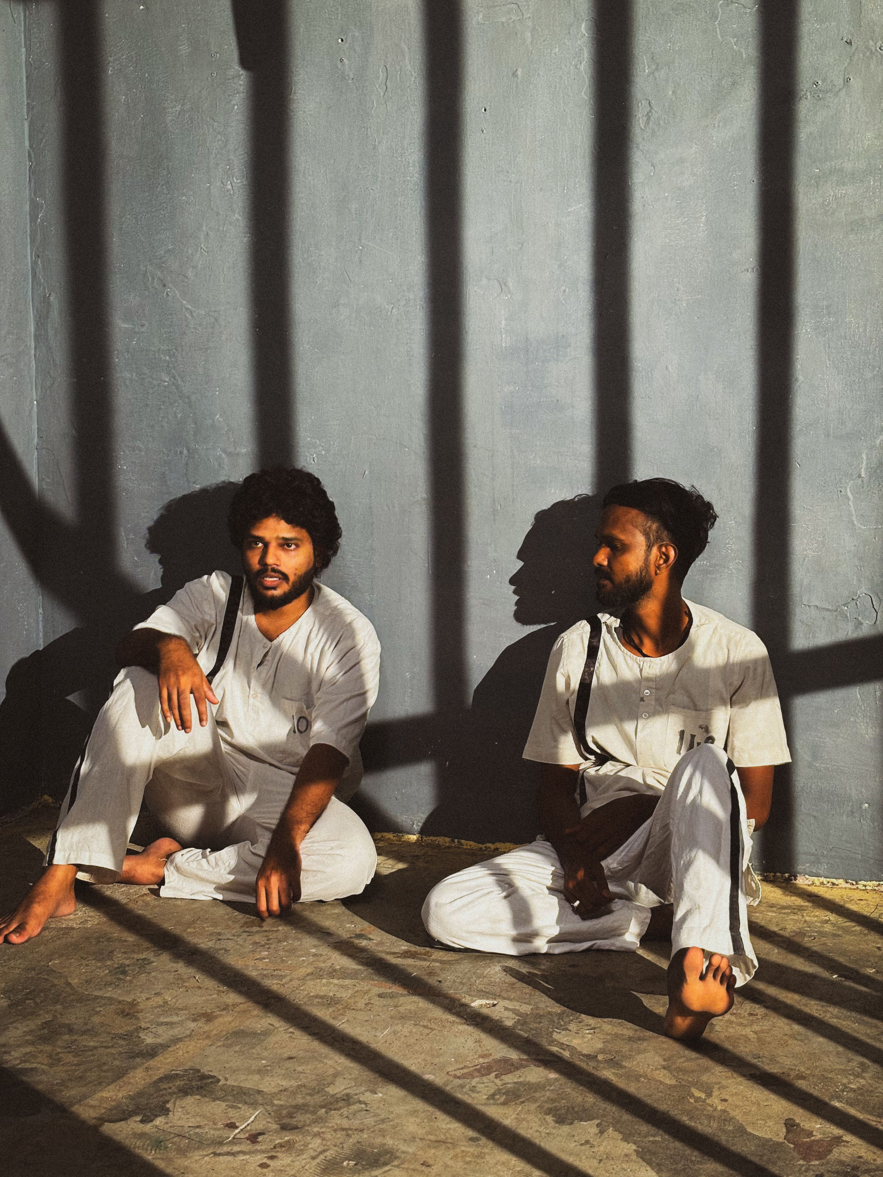 Two Men Sitting in Dimly Lit Prison Cell · Free Stock Photo