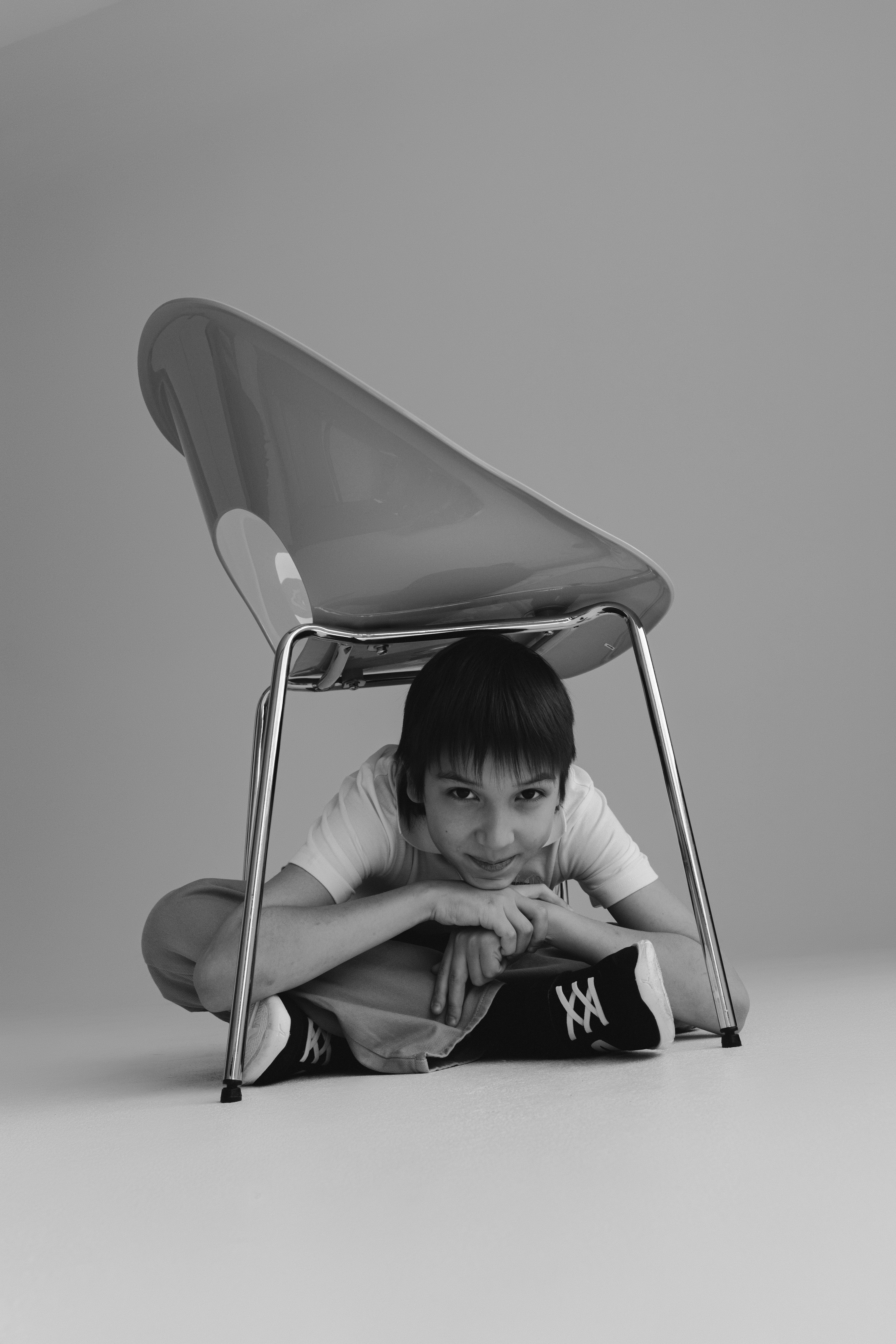 Child Playfully Hides Under Modern Chair · Free Stock Photo