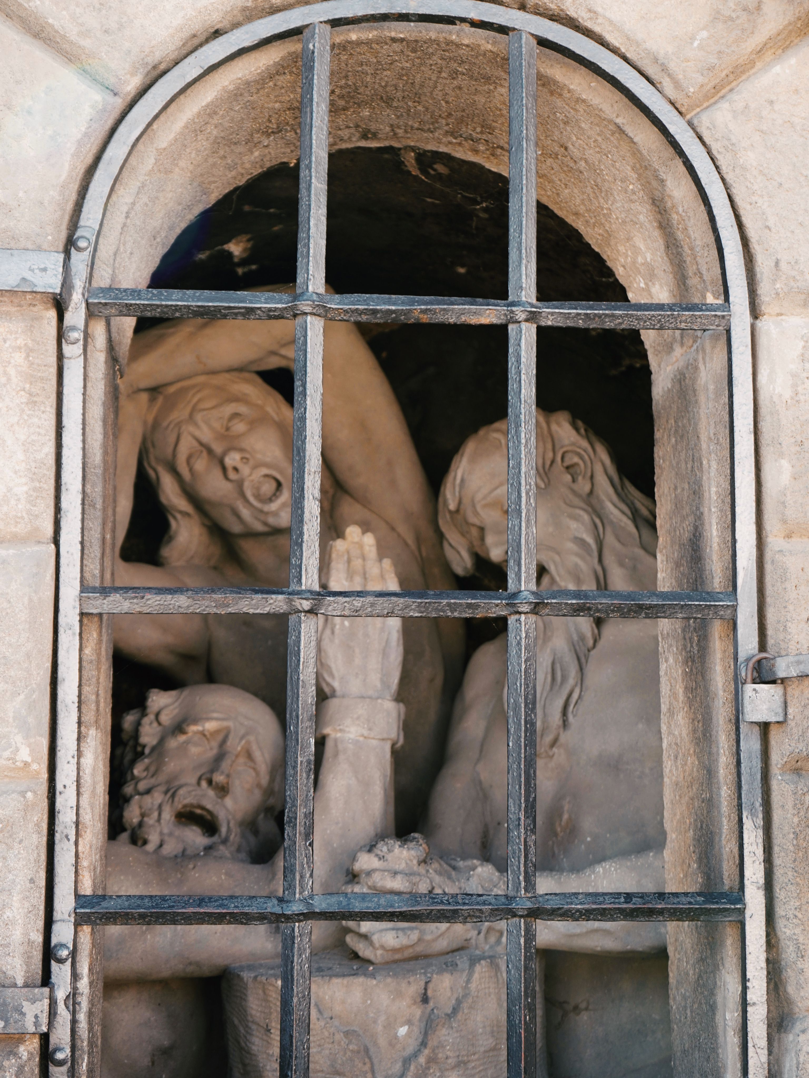 Dramatic Sculptures Behind Iron Bars · Free Stock Photo