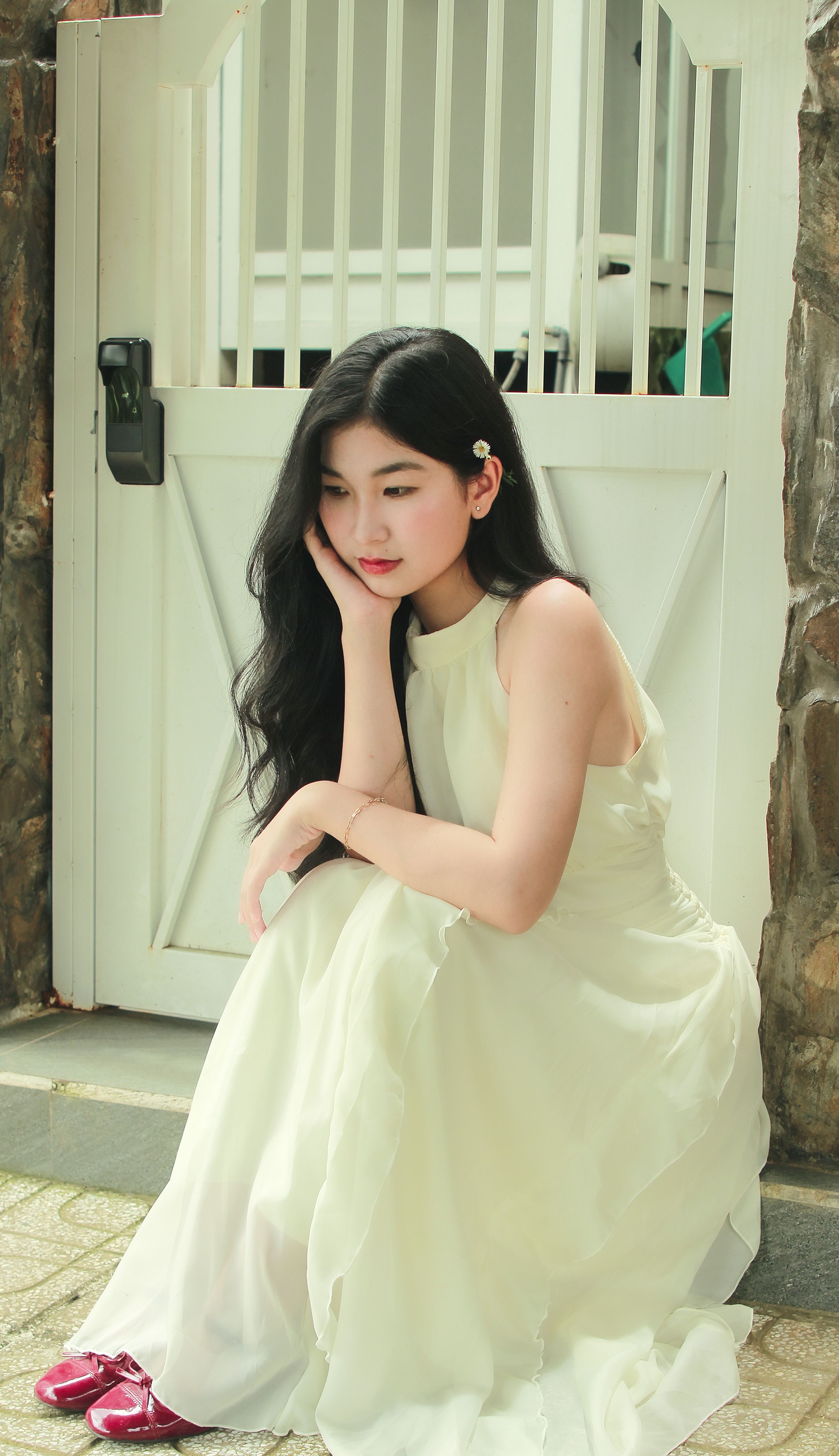 Elegant woman in white dress sitting by gate · Free Stock Photo