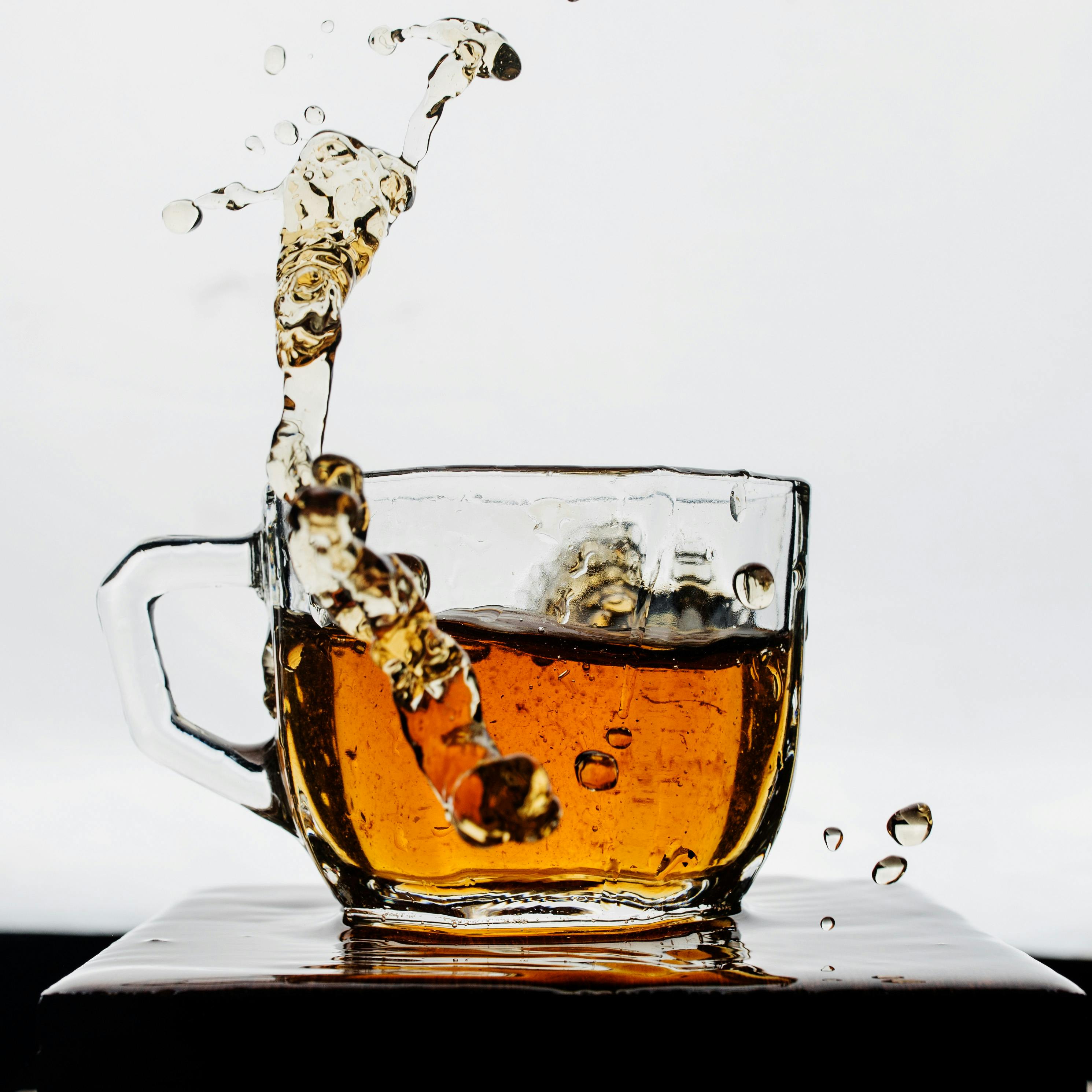 Splashing Tea in Glass Mug Against White Background · Free Stock Photo