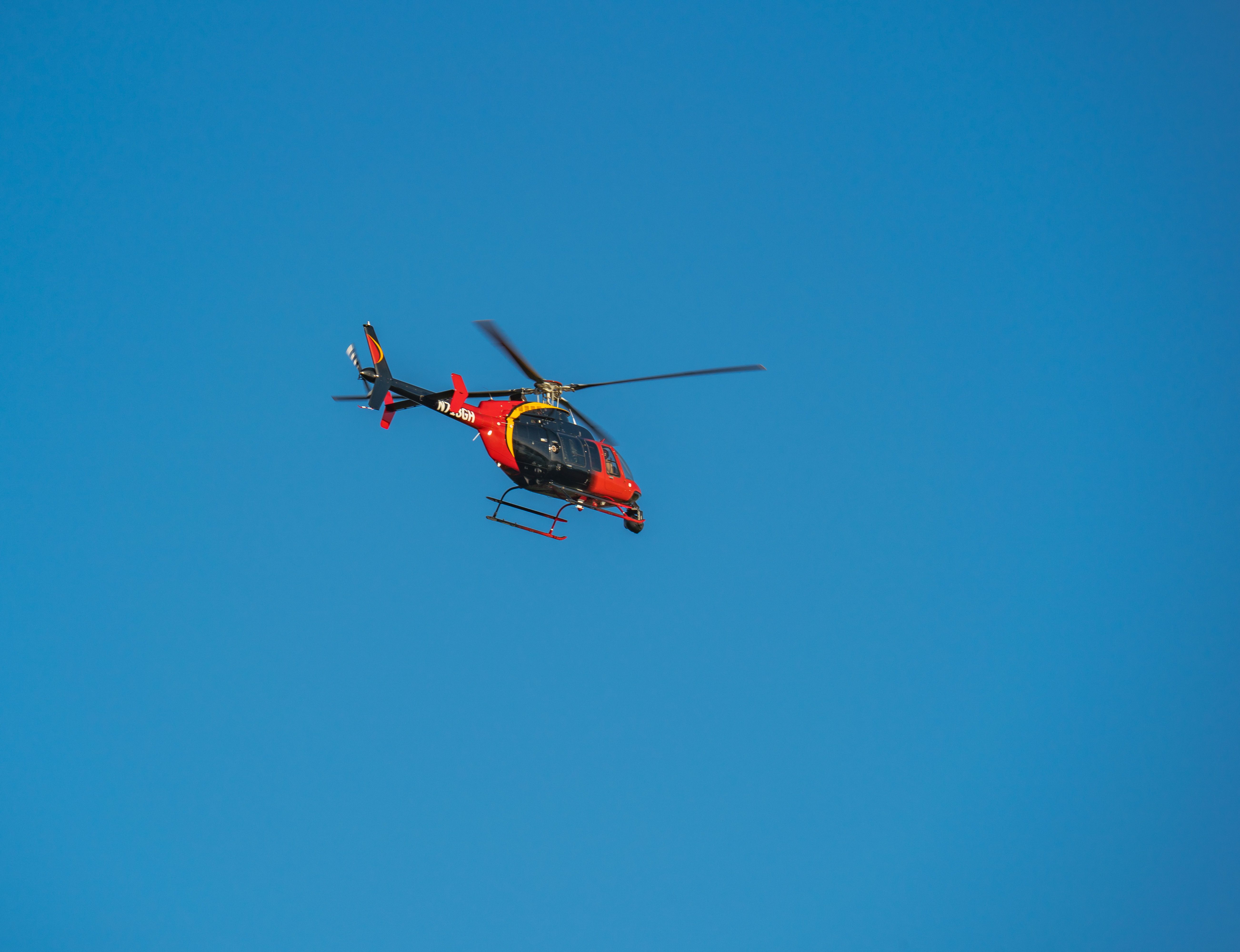 Red Helicopter Flying Against a Clear Blue Sky · Free Stock Photo
