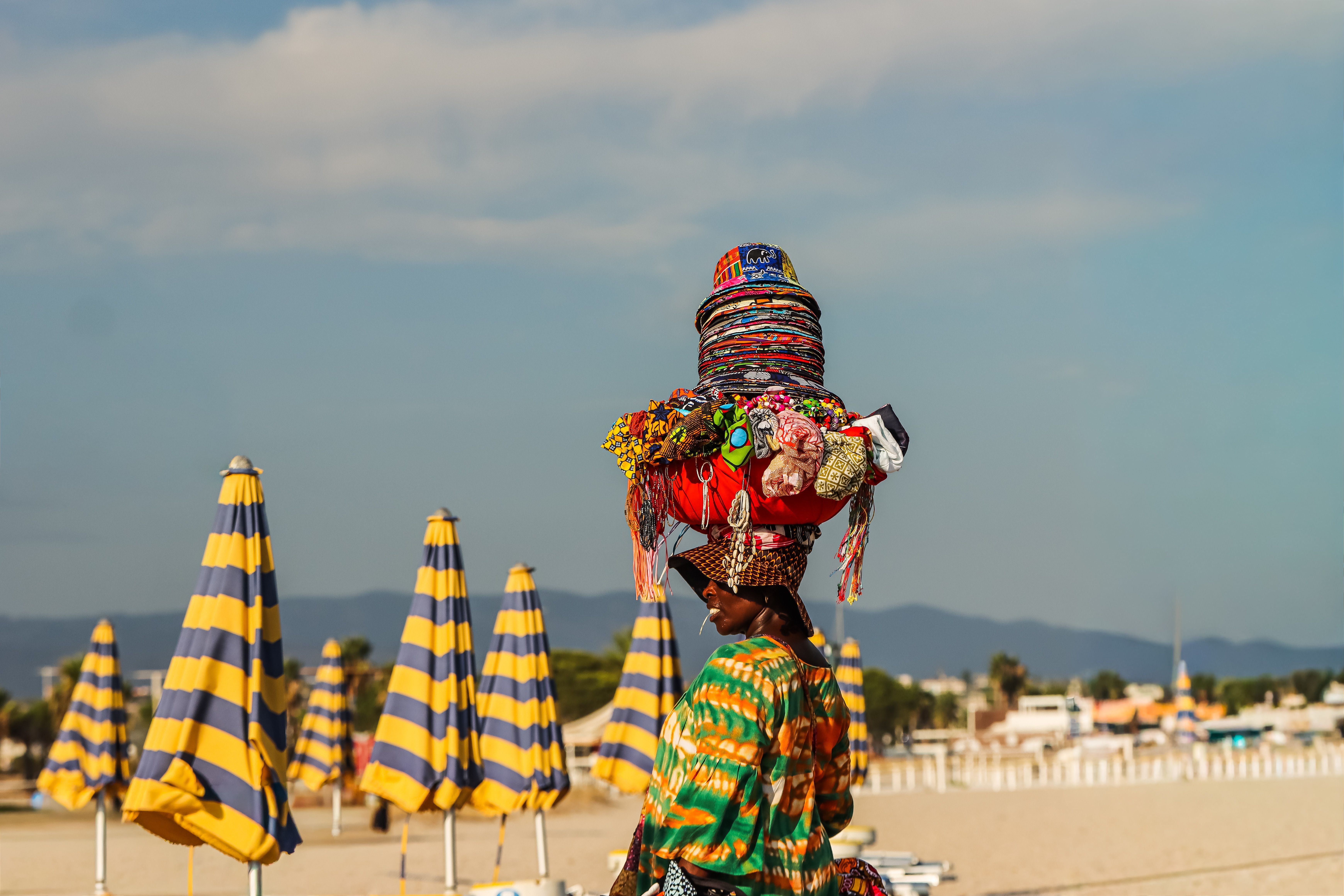 African Vendor on Sardinian Beach with Umbrellas · Free Stock Photo