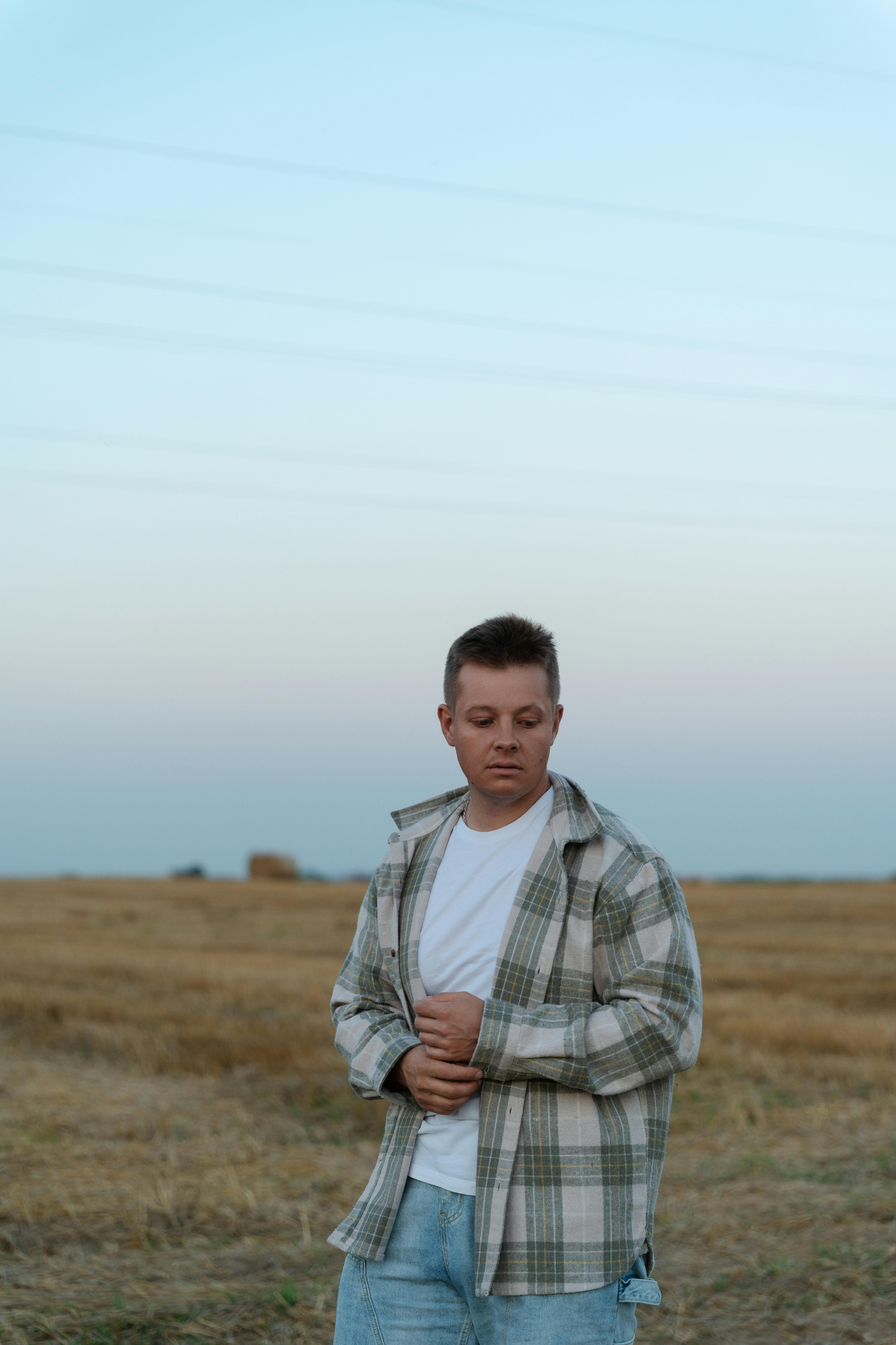 Person in Plaid Shirt Standing in Open Field at Dusk · Free Stock Photo