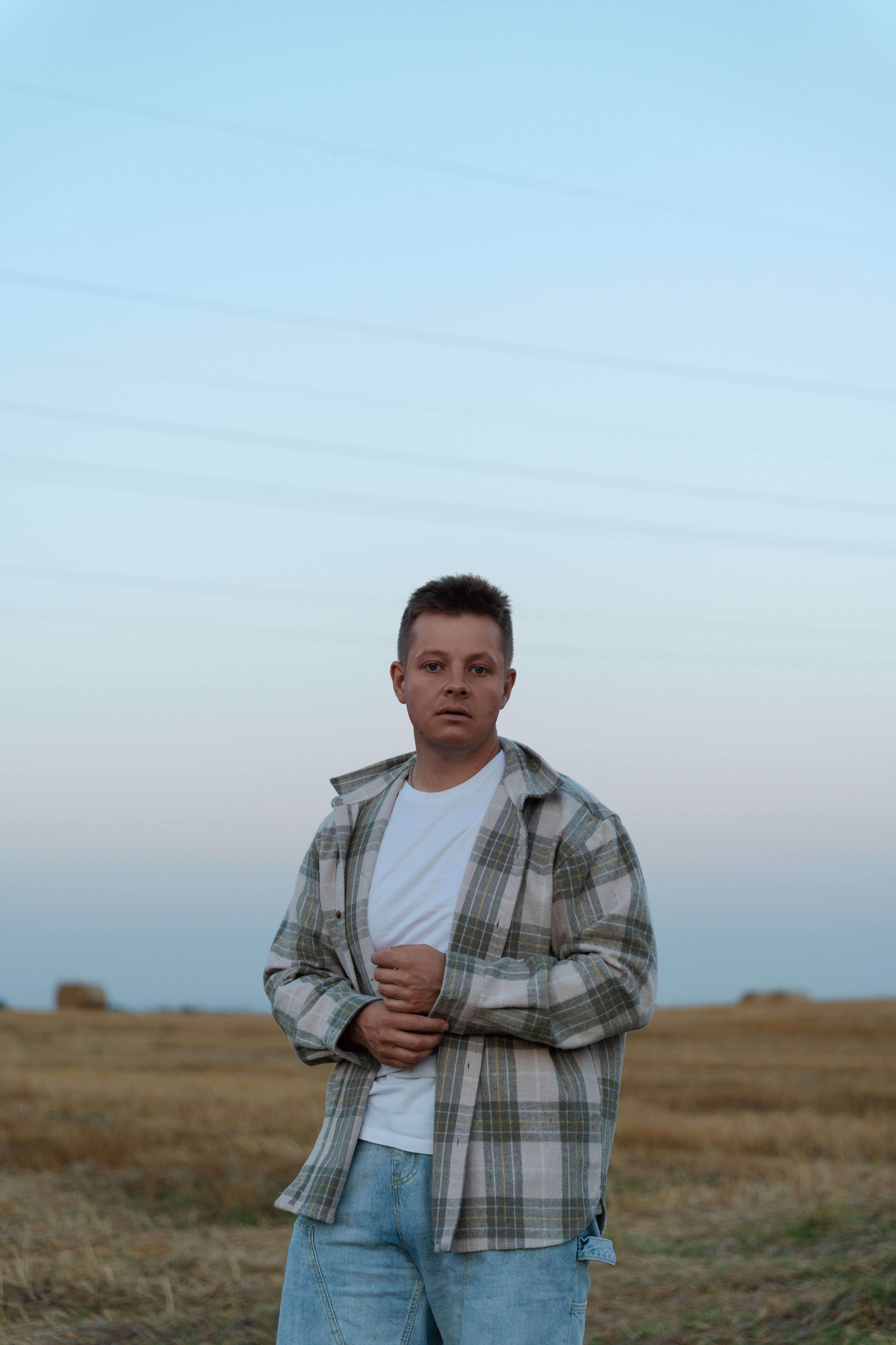 Person in Plaid Shirt Standing in Rural Field at Dusk · Free Stock Photo