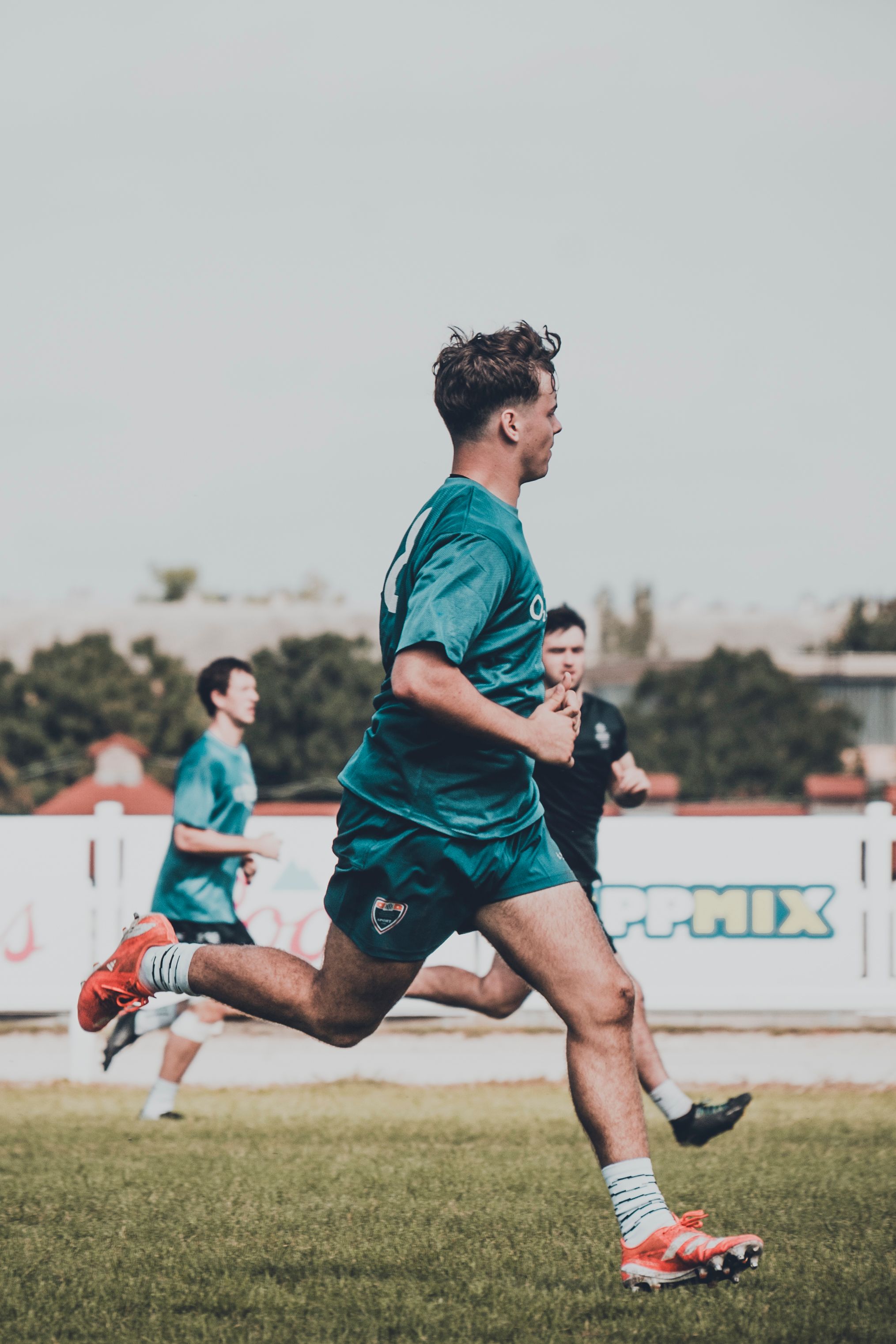 Young Male Athletes Running on Soccer Field · Free Stock Photo