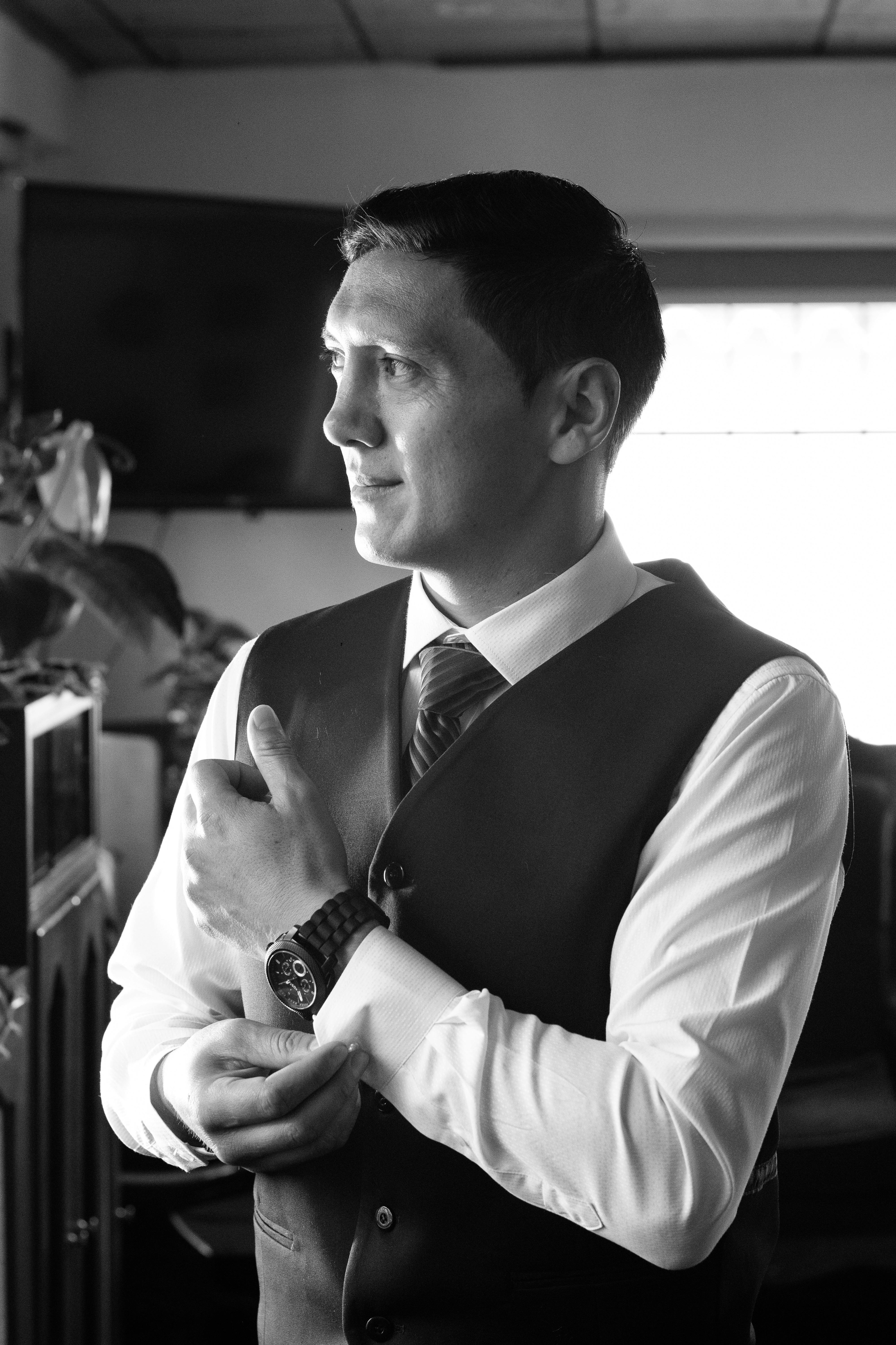 Stylish Man Adjusting Cufflinks in Black and White · Free Stock Photo