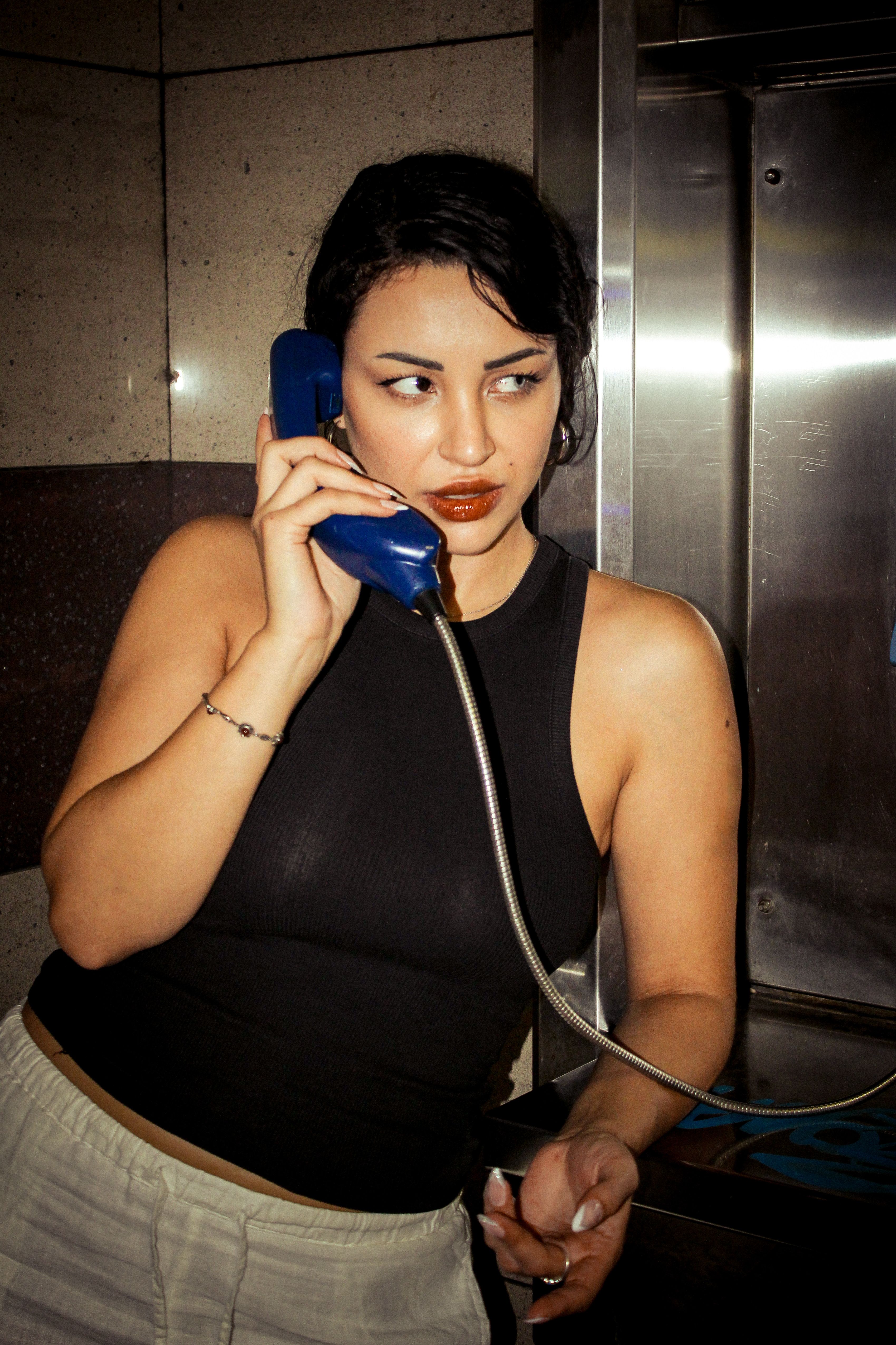 Woman in Black Top Using a Payphone · Free Stock Photo