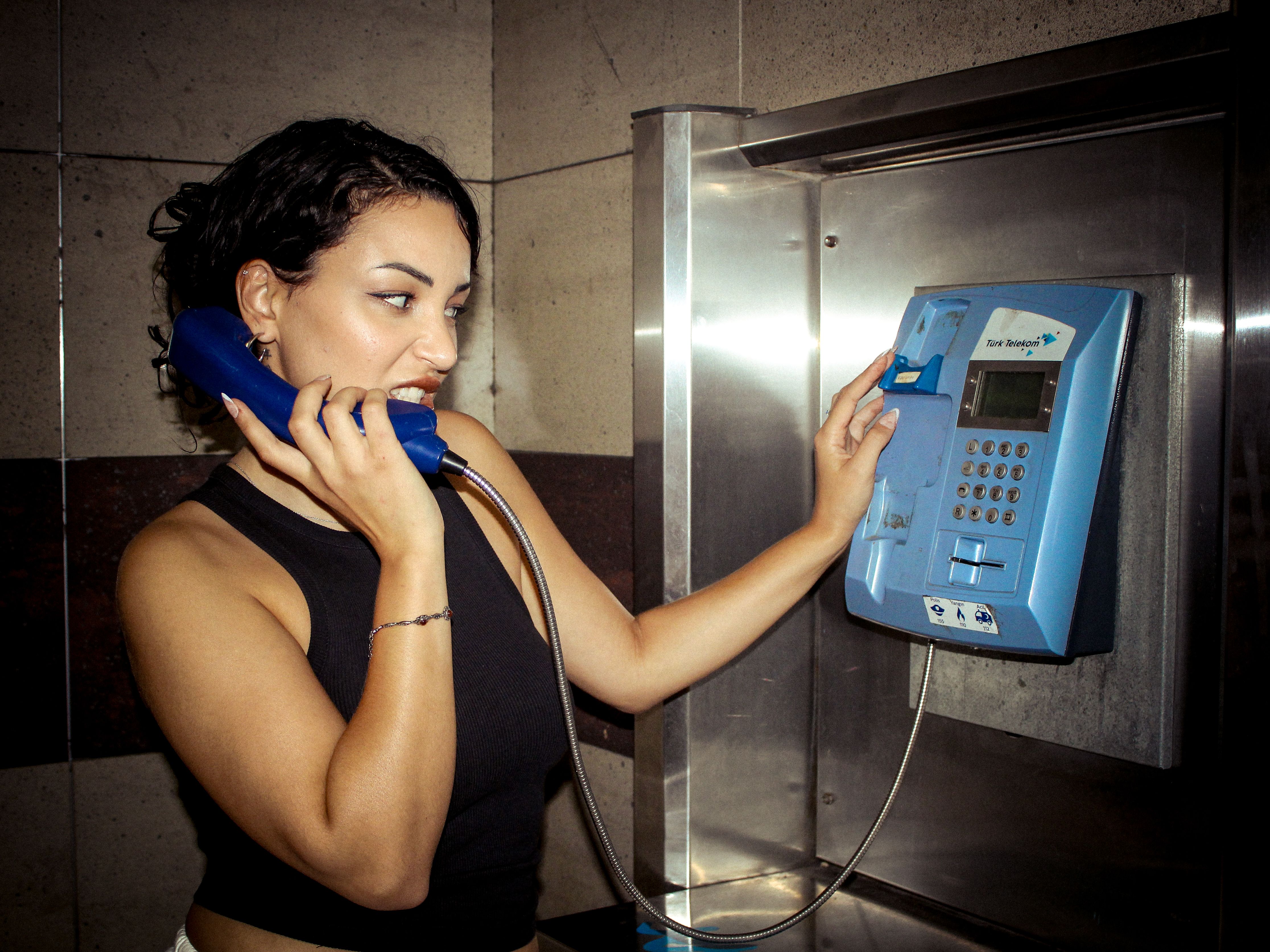 Woman Making Serious Phone Call at Payphone Booth · Free Stock Photo