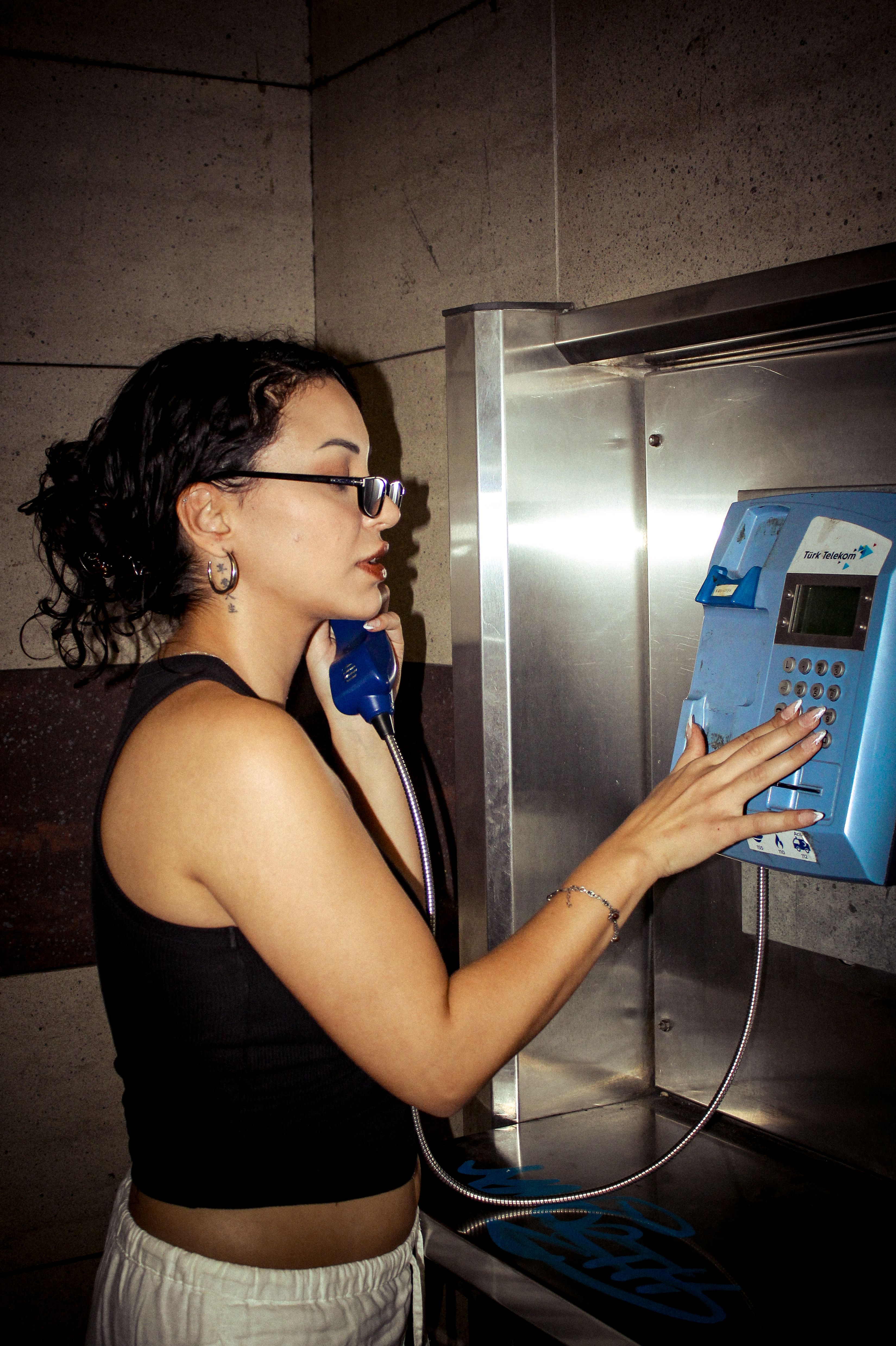 Woman using a public payphone in an urban setting · Free Stock Photo