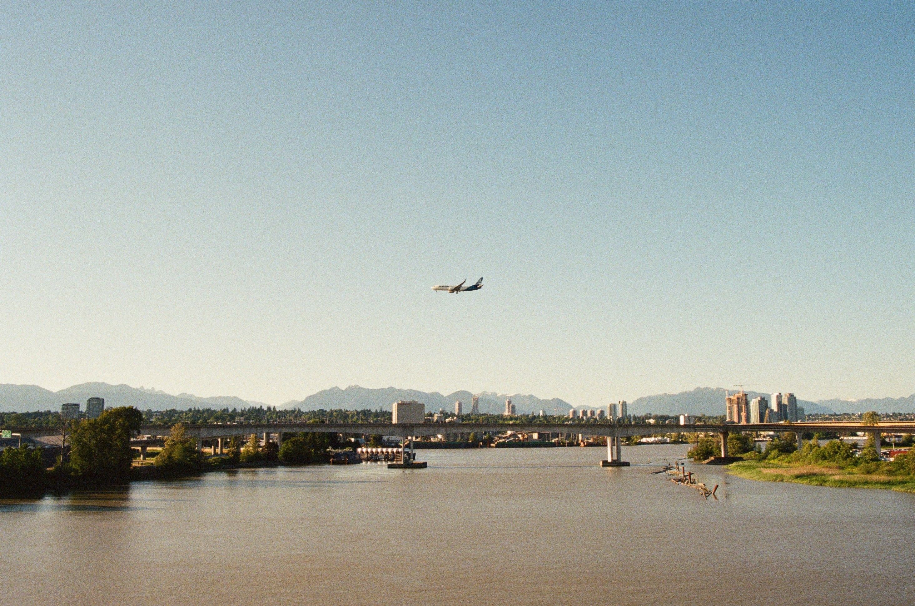 Airplane Over River with Cityscape Background · Free Stock Photo