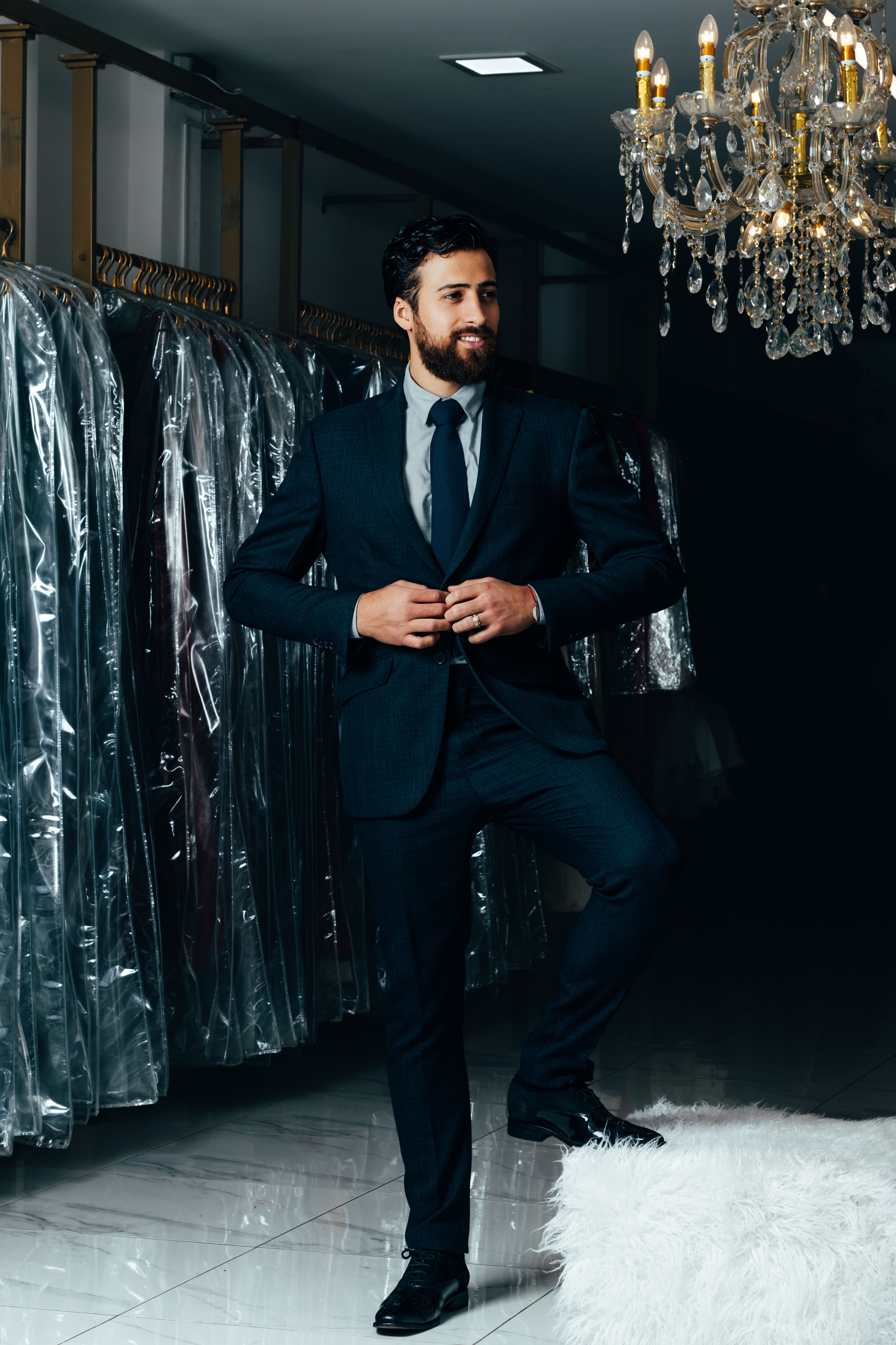 Elegant Man in Suit Standing by Clothing Racks · Free Stock Photo