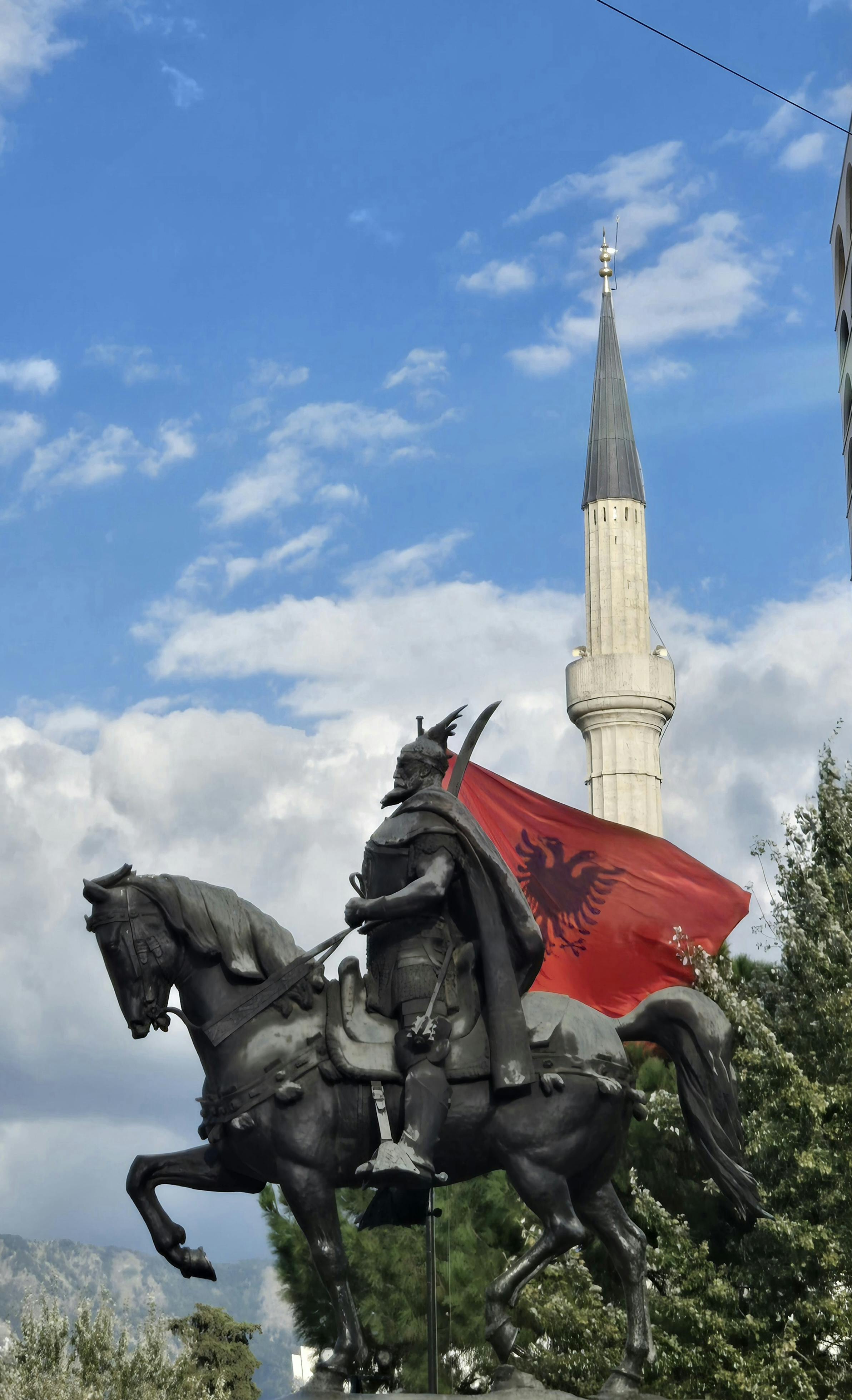 Skanderbeg Monument with Albanian Flag and Mosque · Free Stock Photo
