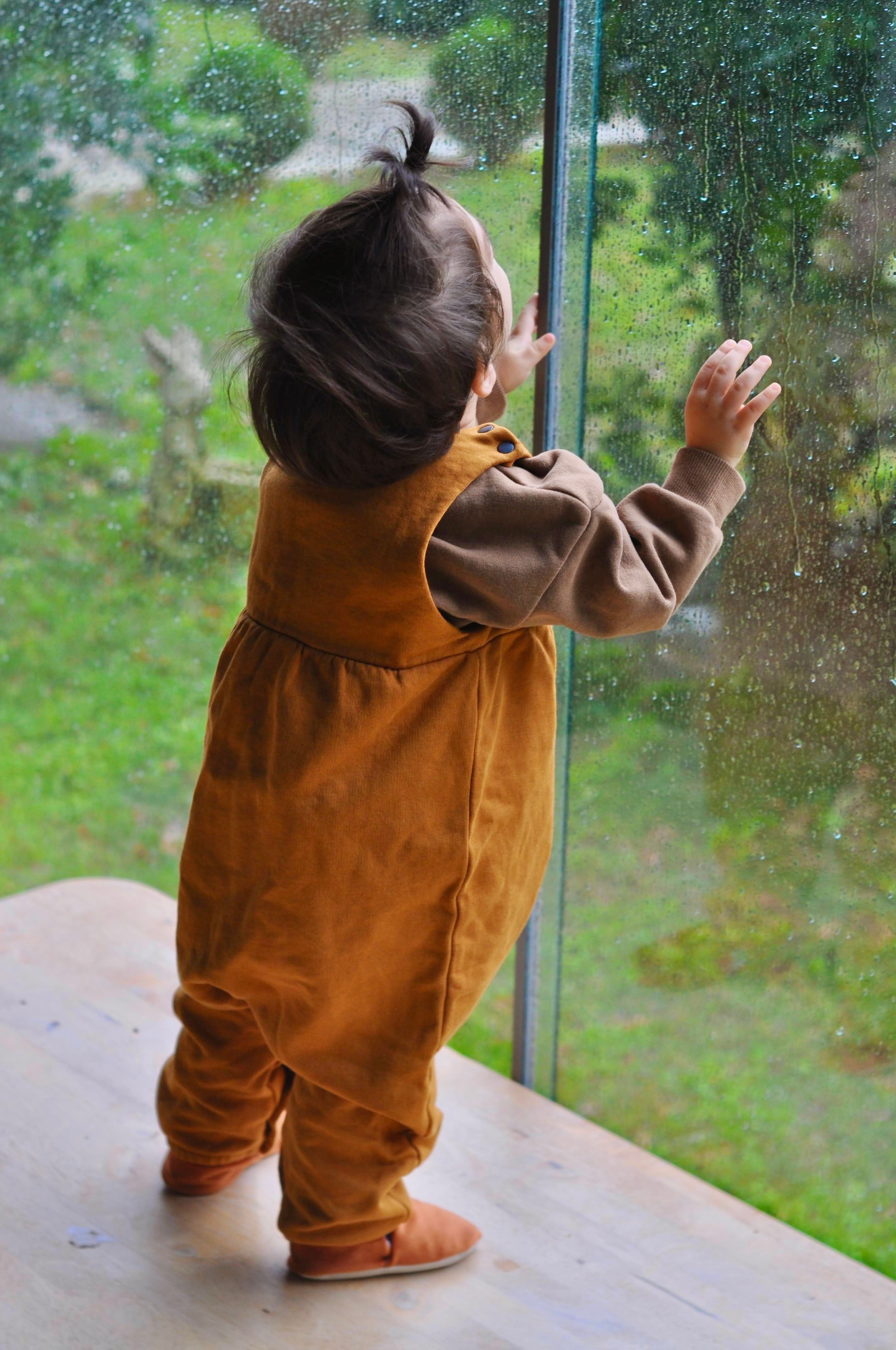 Curious Toddler Looking Through Rainy Window · Free Stock Photo
