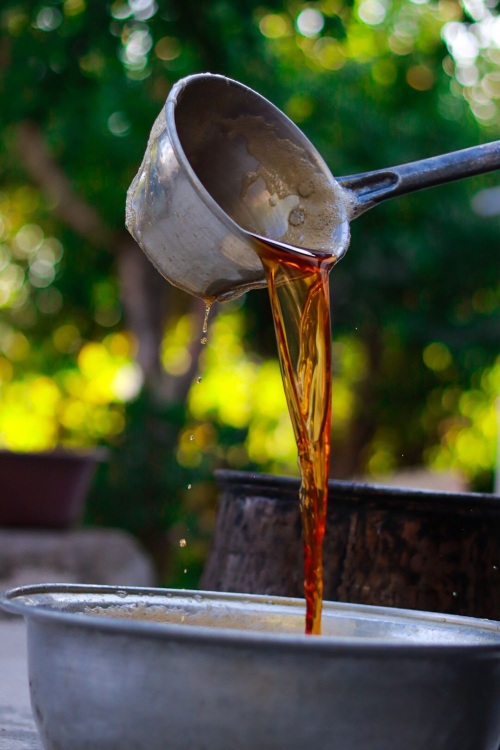 Pouring Golden Liquid into Basin Outdoors · Free Stock Photo
