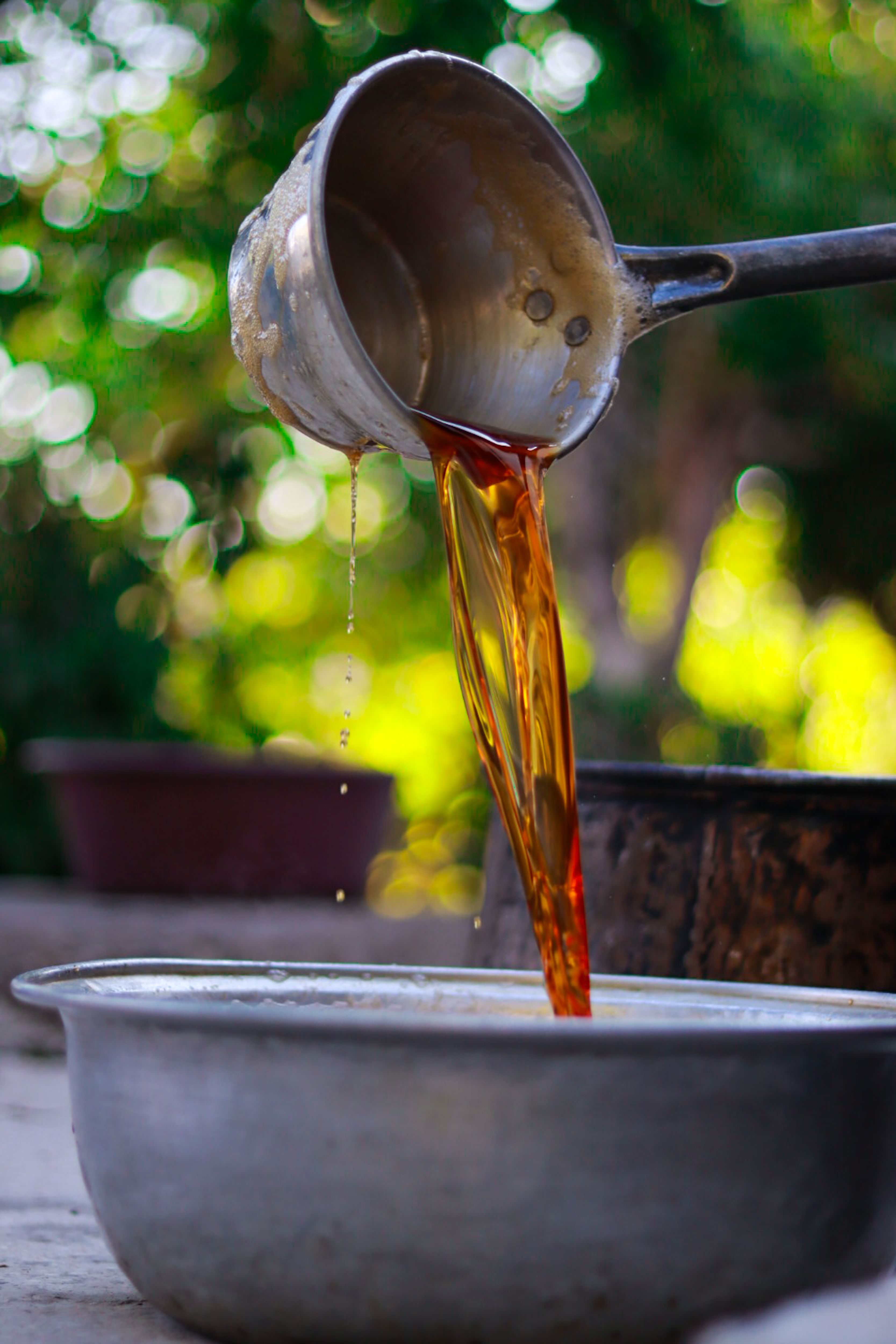 Pouring Golden Liquid into Basin Outdoors · Free Stock Photo
