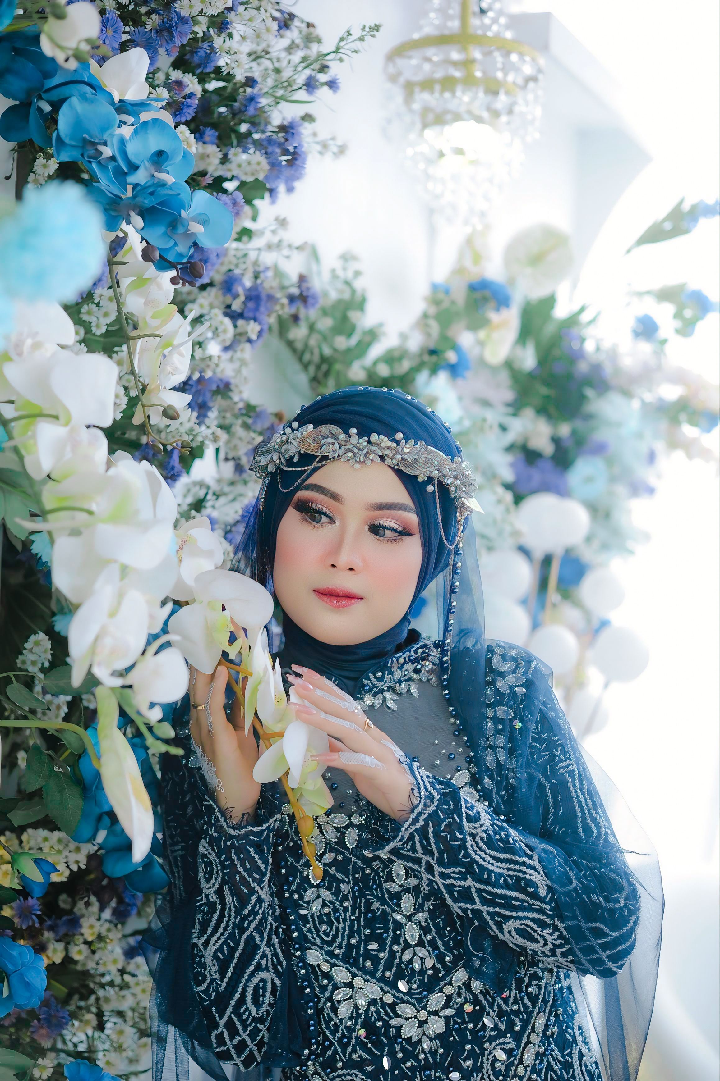 Elegant Woman in Blue Hijab Amidst Floral Decor · Free Stock Photo