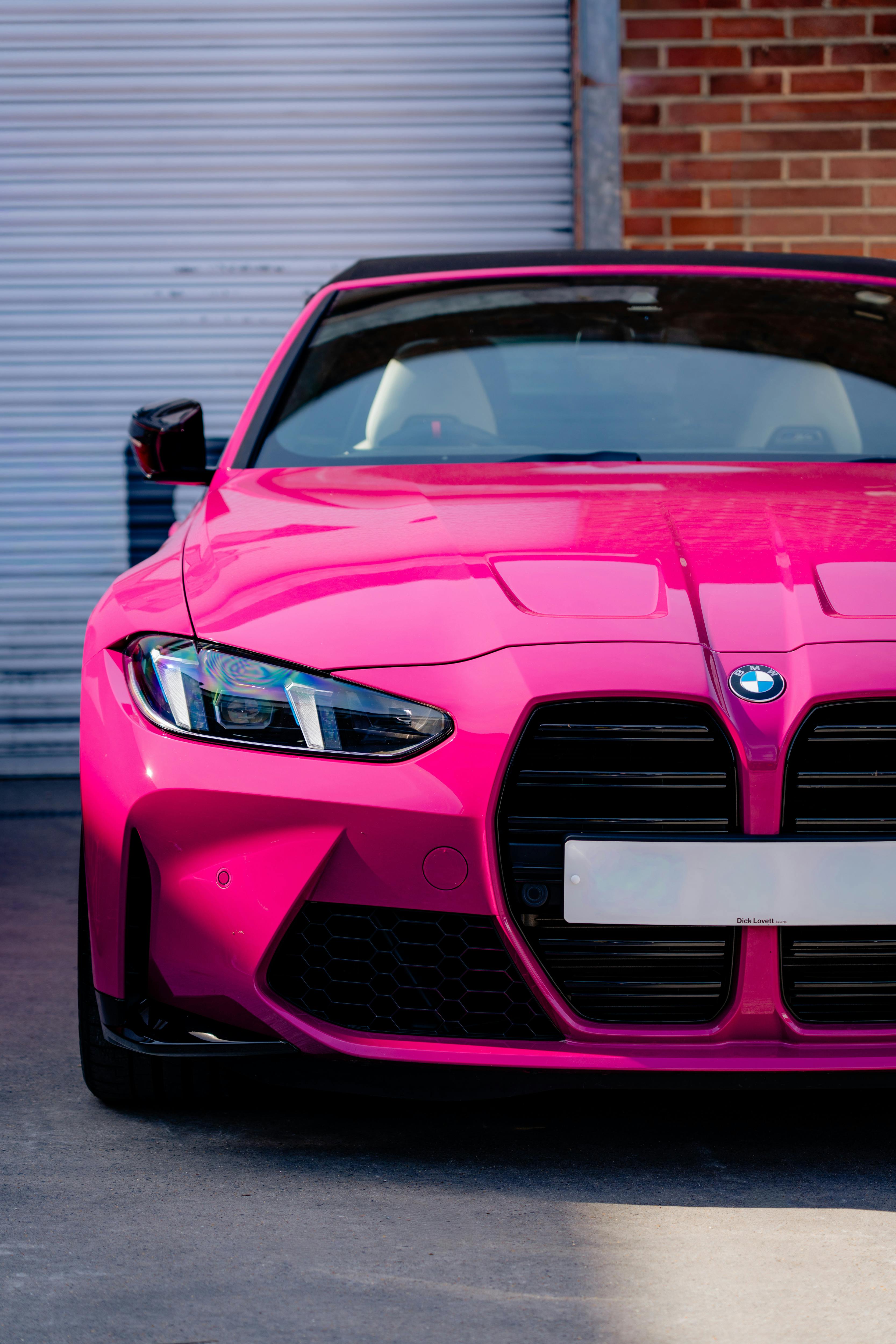 Vibrant Pink Car Parked Against Industrial Background · Free Stock Photo